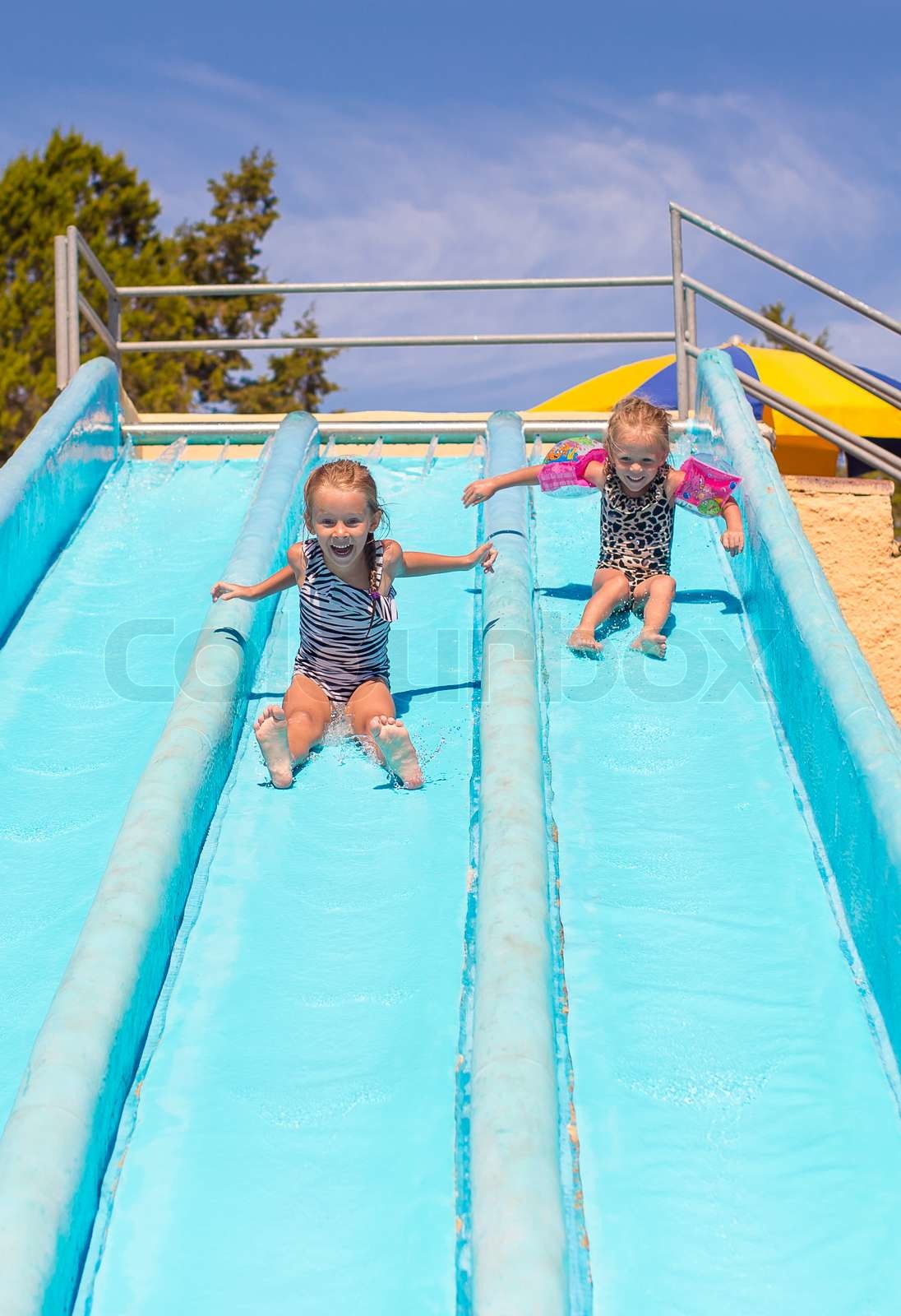Cute girls on water slide at aquapark during summer holiday | Stock ...