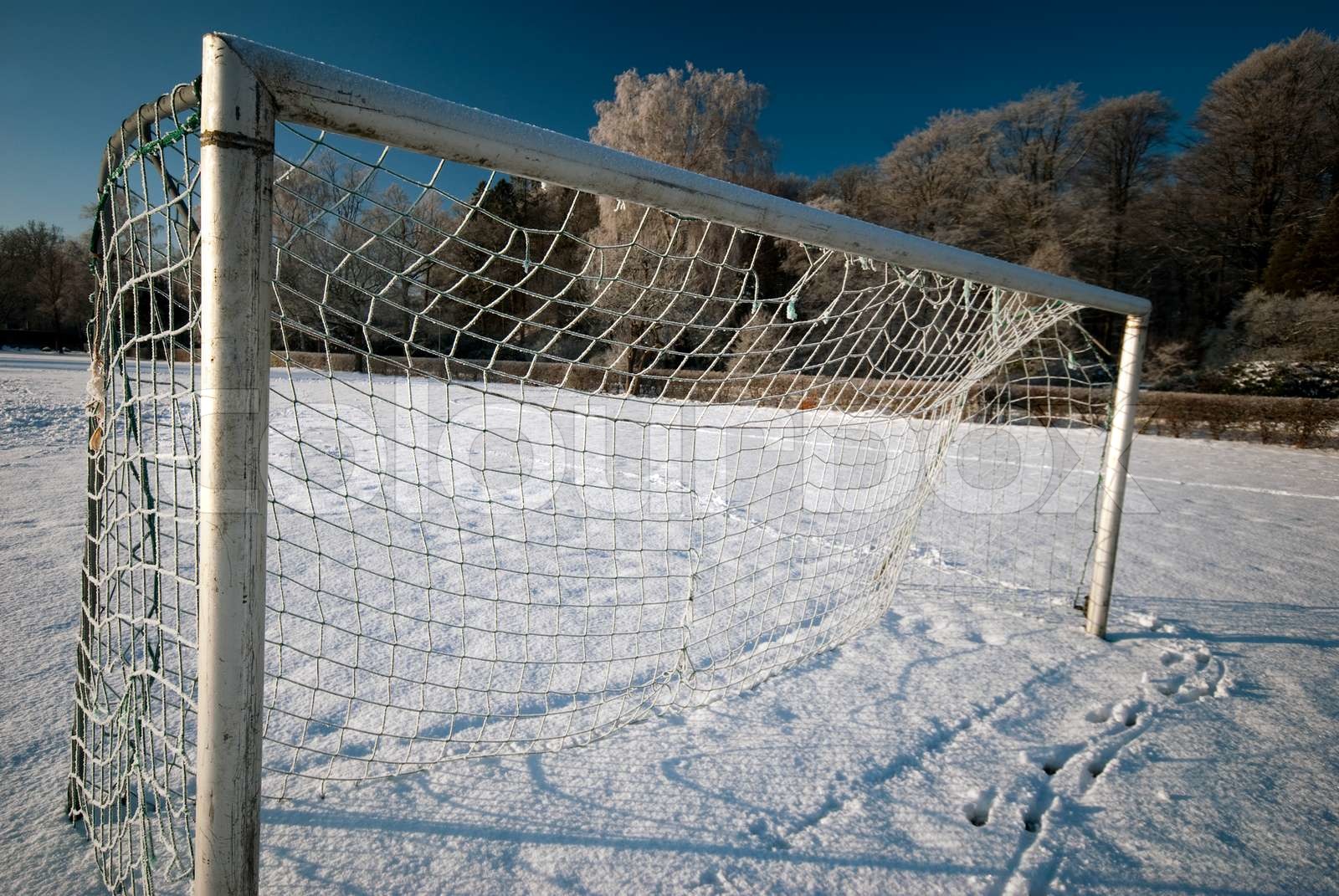 Soccer goal with icy net and soccer field outdoors in winter snow all ...