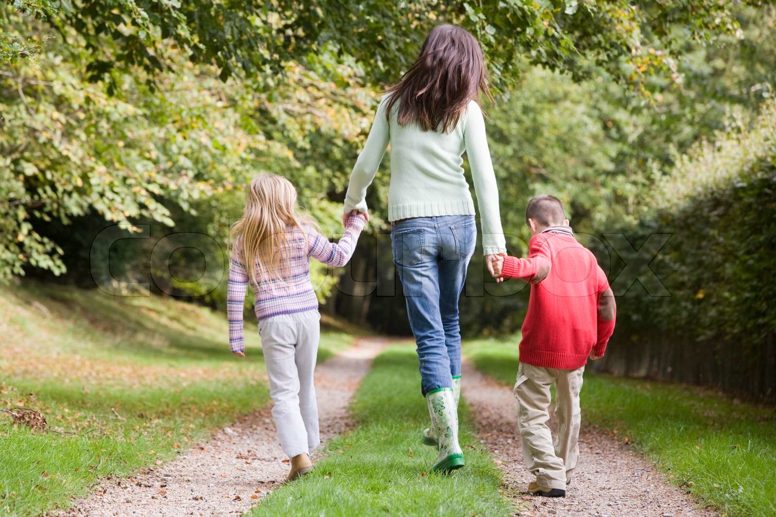 Mother and children walking on woodland path in autumn | Stock image ...