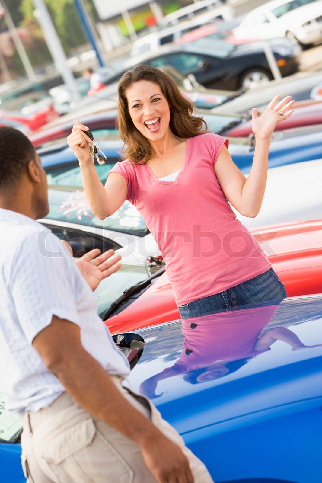 Woman picking up keys to new car from lot | Stock image | Colourbox