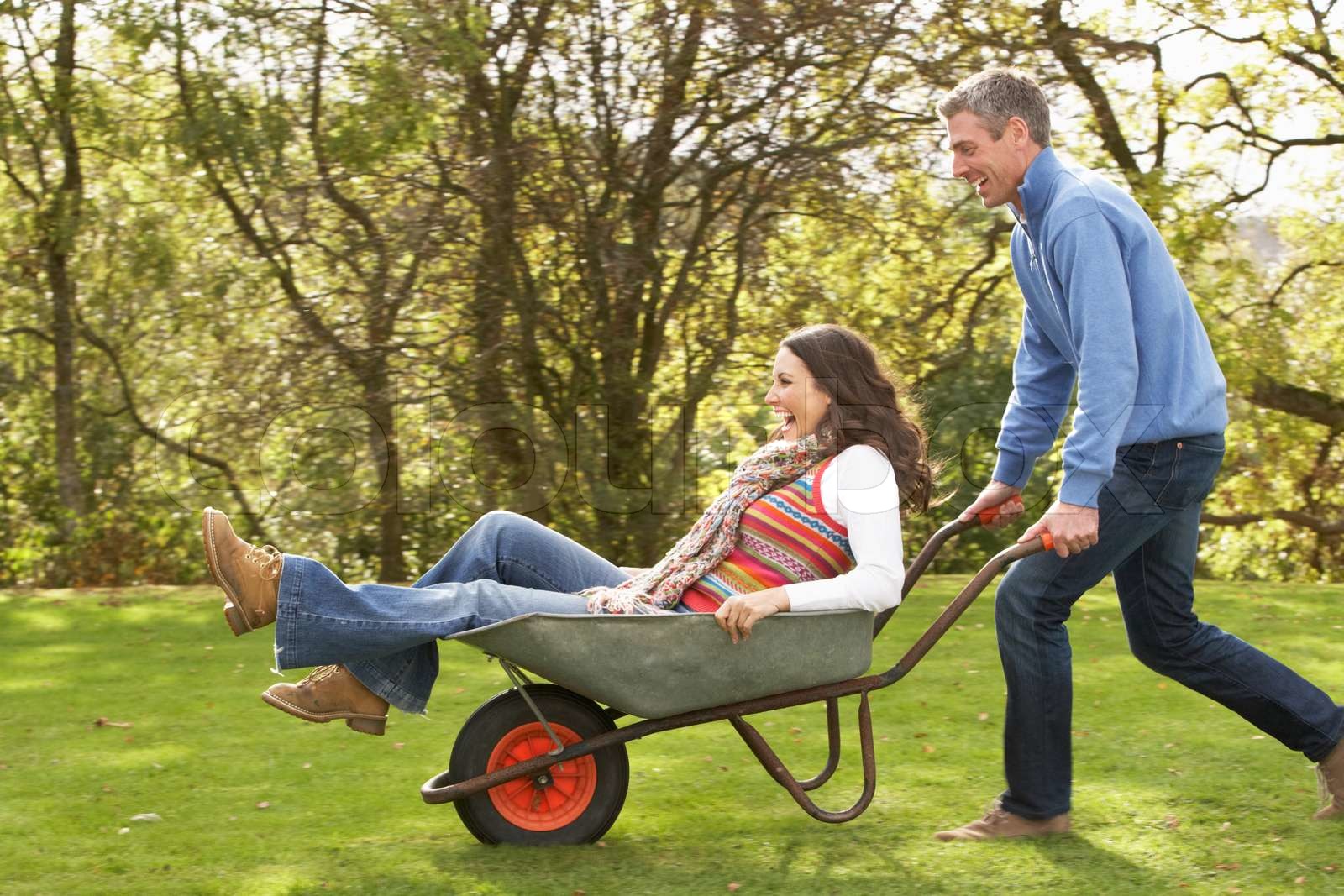 Couple With Man Giving Woman Ride In Wheelbarrow | Stock image | Colourbox