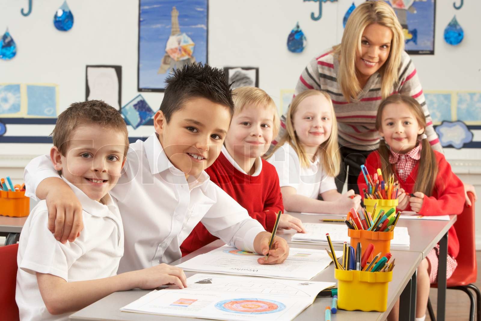 Group Of Primary Schoolchildren And Teacher Working At Desks In ...