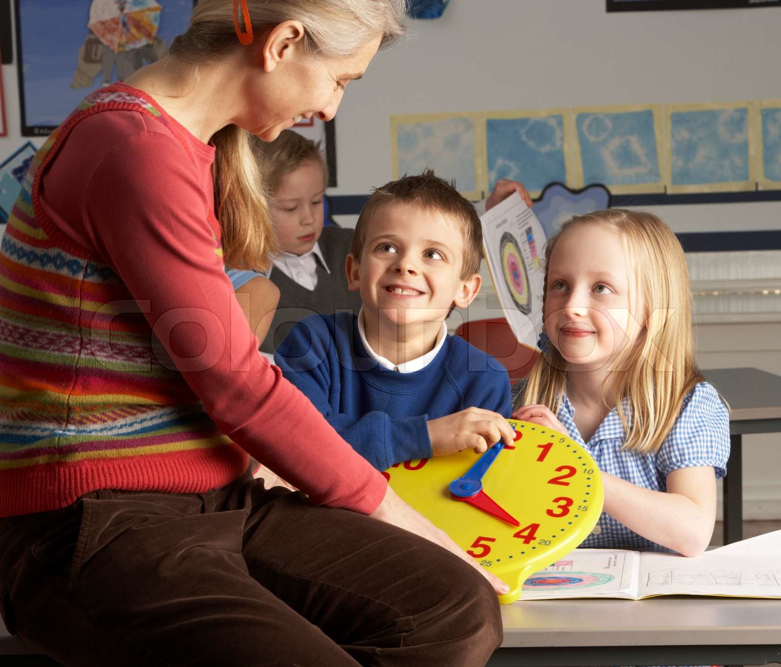 Kvinde lærer i Primary School lære børn at fortælle tid i ...