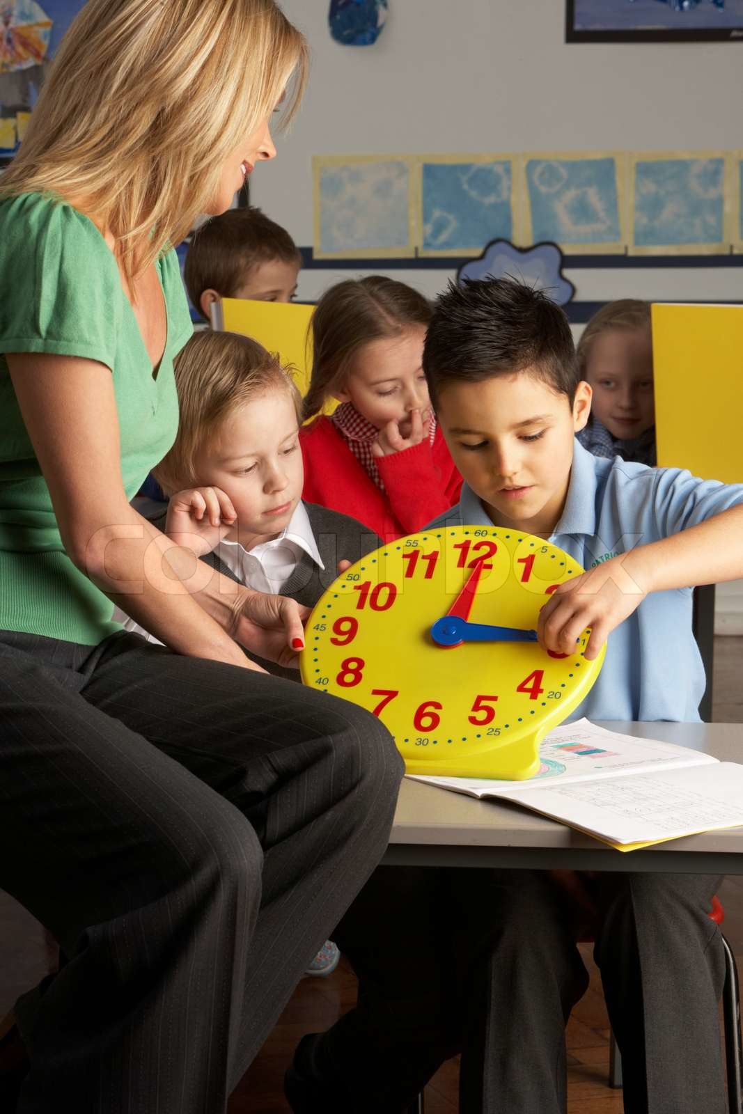 Female Teacher In Primary School Teaching Children To Tell Time In ...