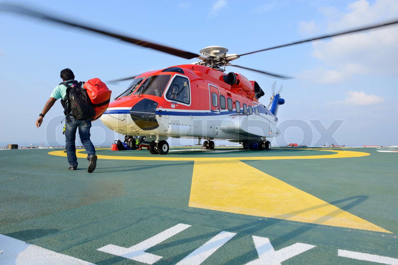 passenger carry his baggage to embark helicopter at oil rig platform ...