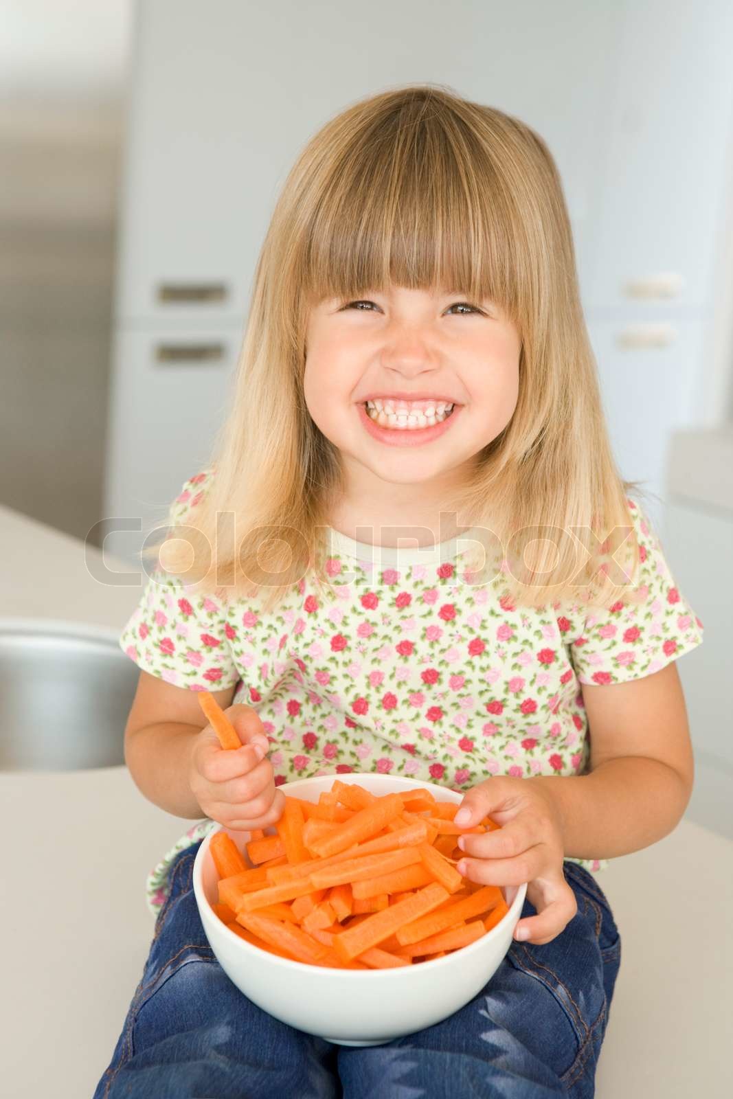 Young girl eating bowl of carrots | Stock image | Colourbox