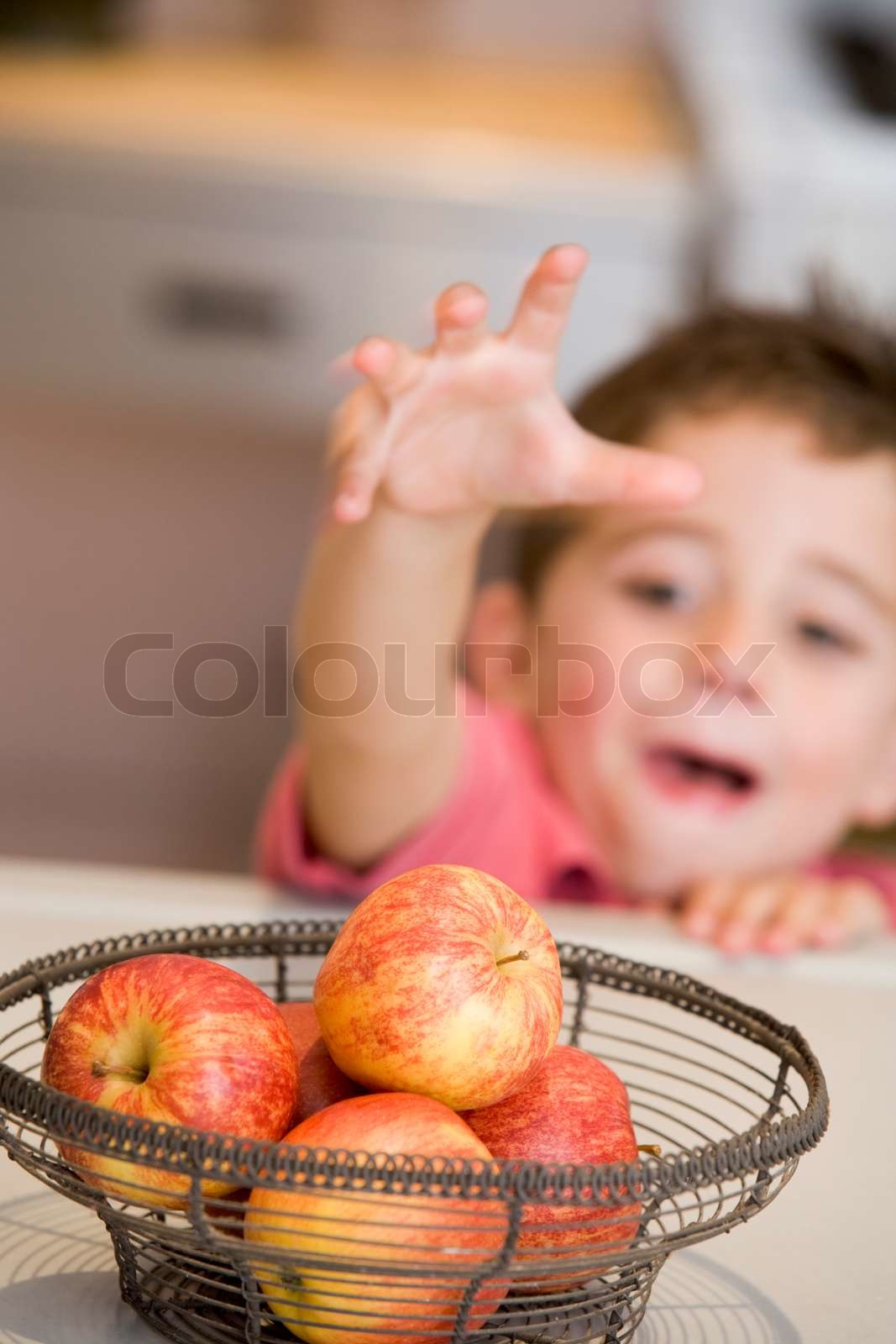 Boy reaching for apple from fruit basket | Stock image | Colourbox