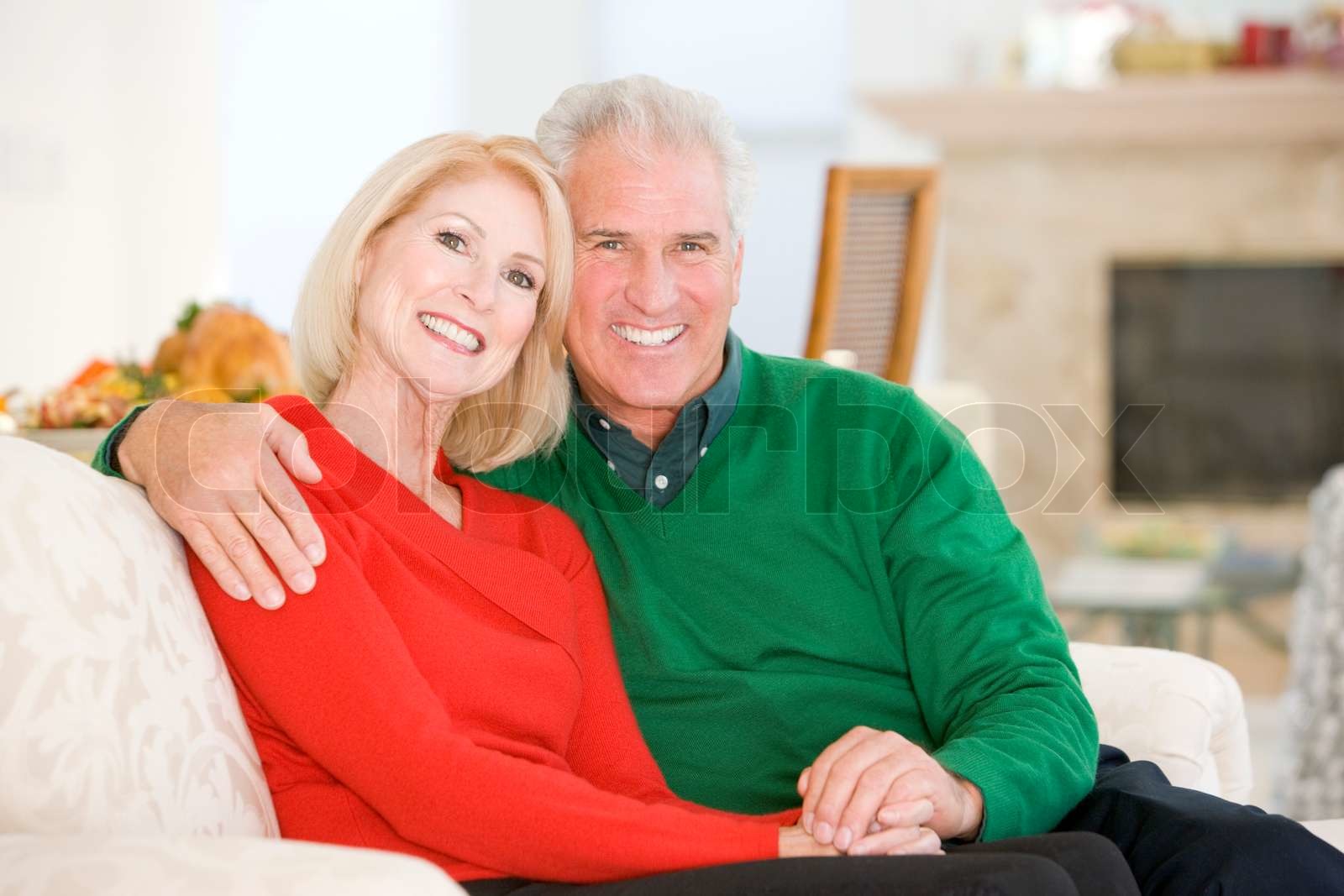 Et ældre, forelsket par sidder i sofaen ved juletid | Stock foto ...