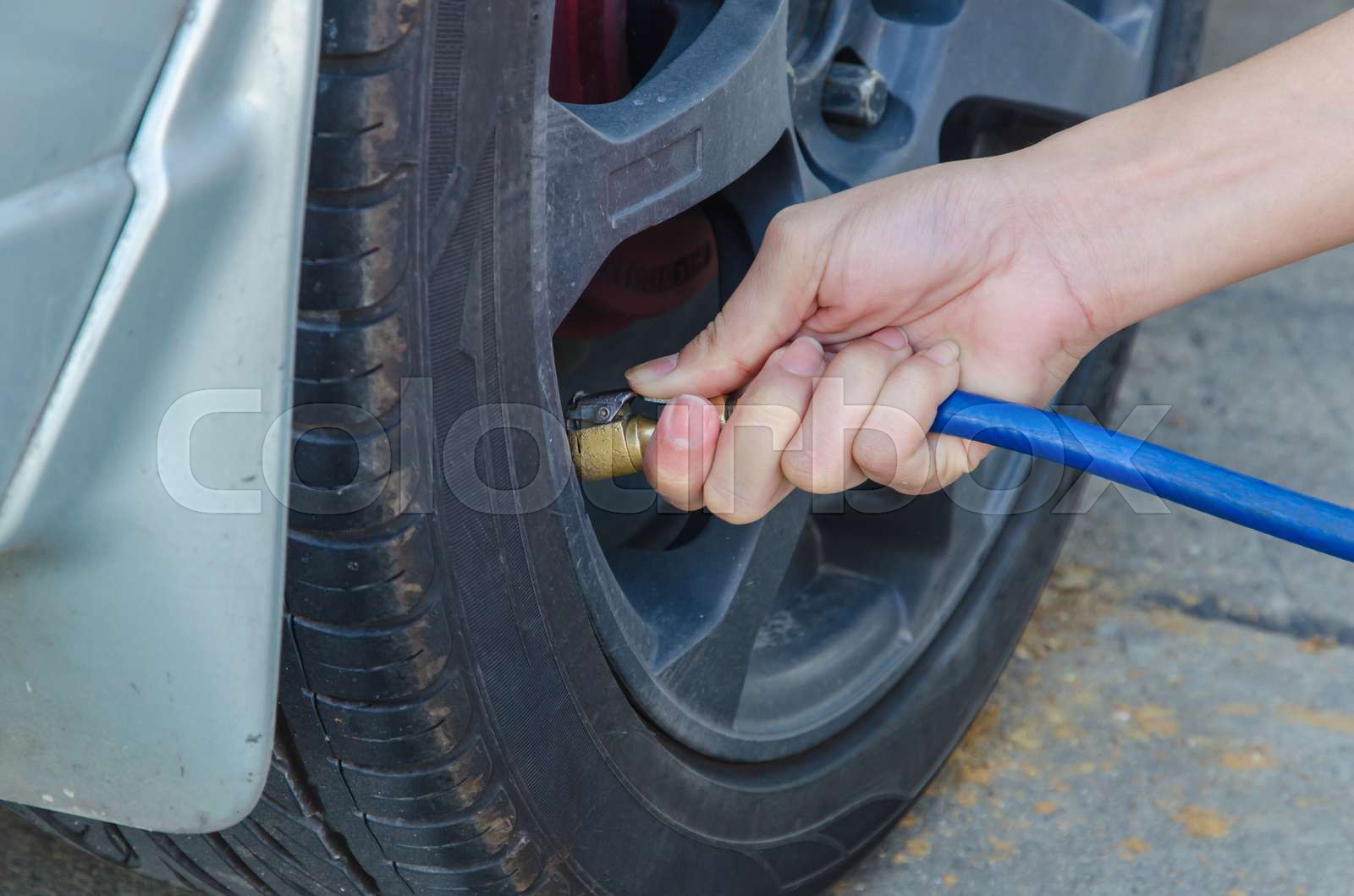 Filling air into a car tire | Stock image | Colourbox
