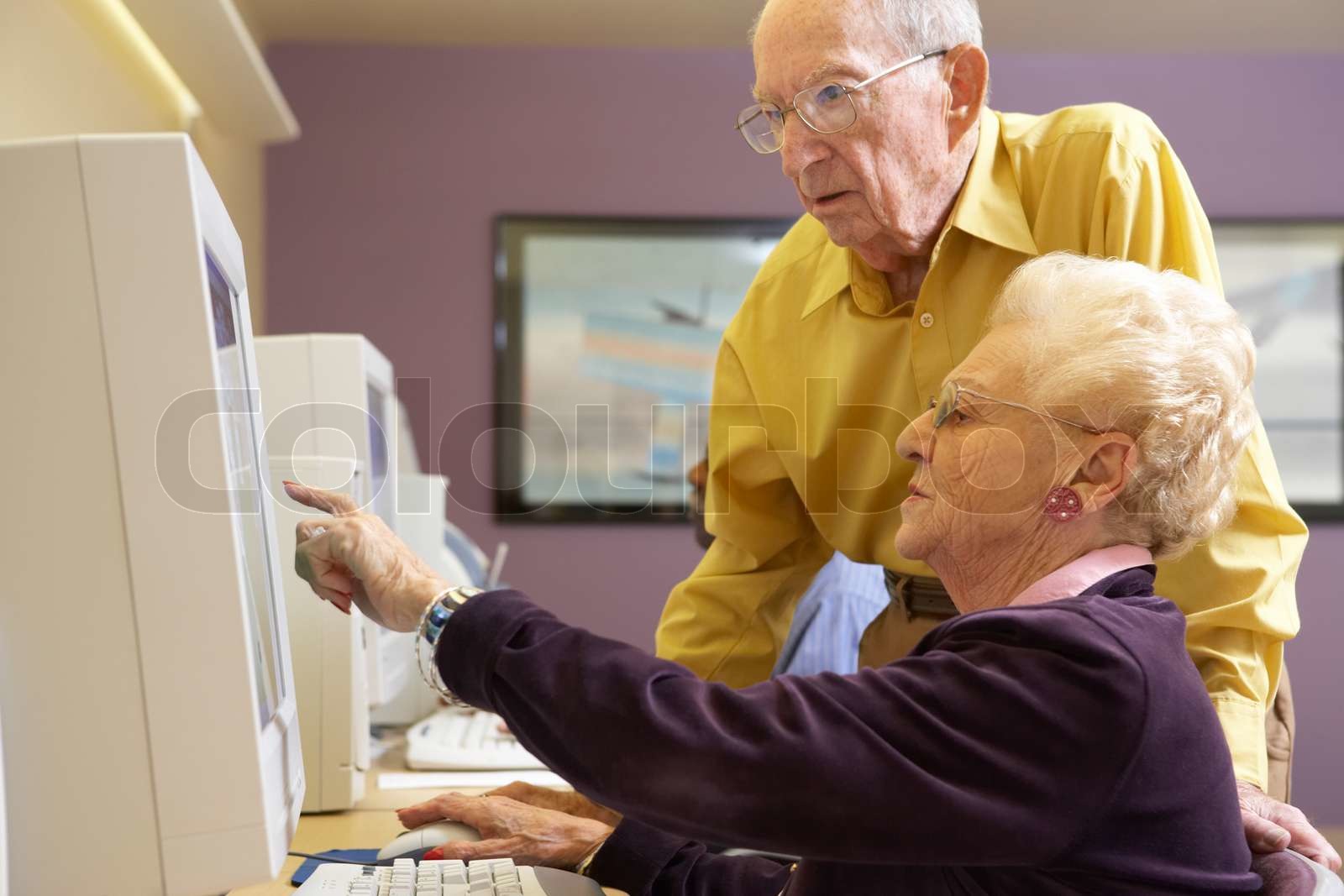 Senior man helping senior woman to use computer | Stock image | Colourbox