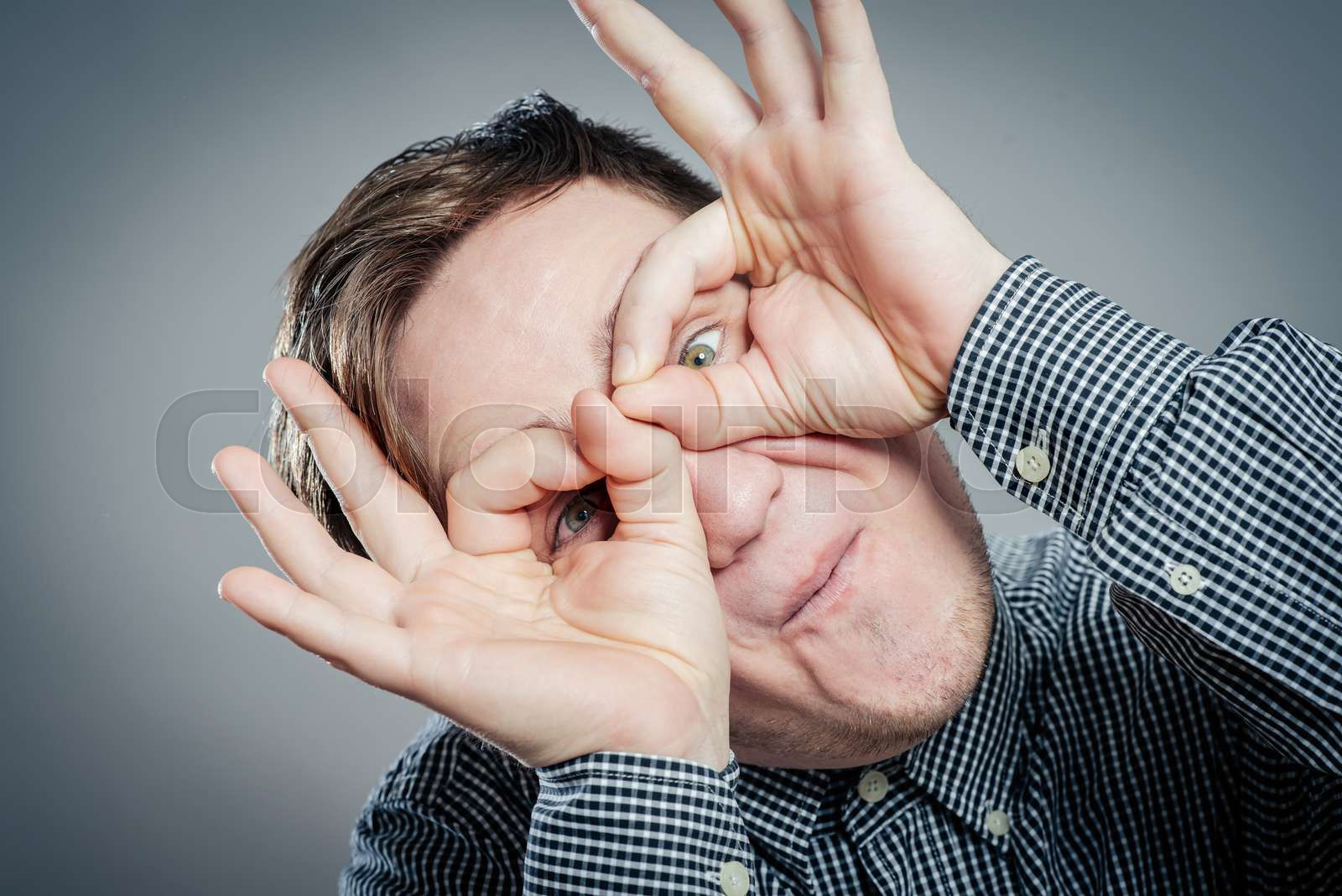 Funny man with hand over eyes, looking through fingers | Stock image ...