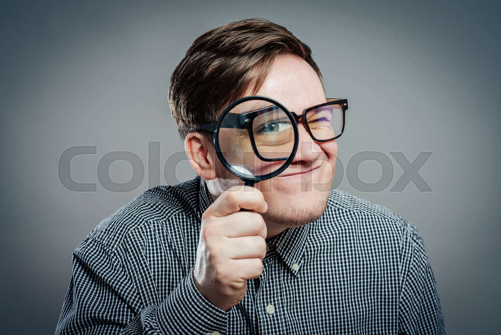 Funny image of a adultman with a magnifying glass, one eye is enlarged ...