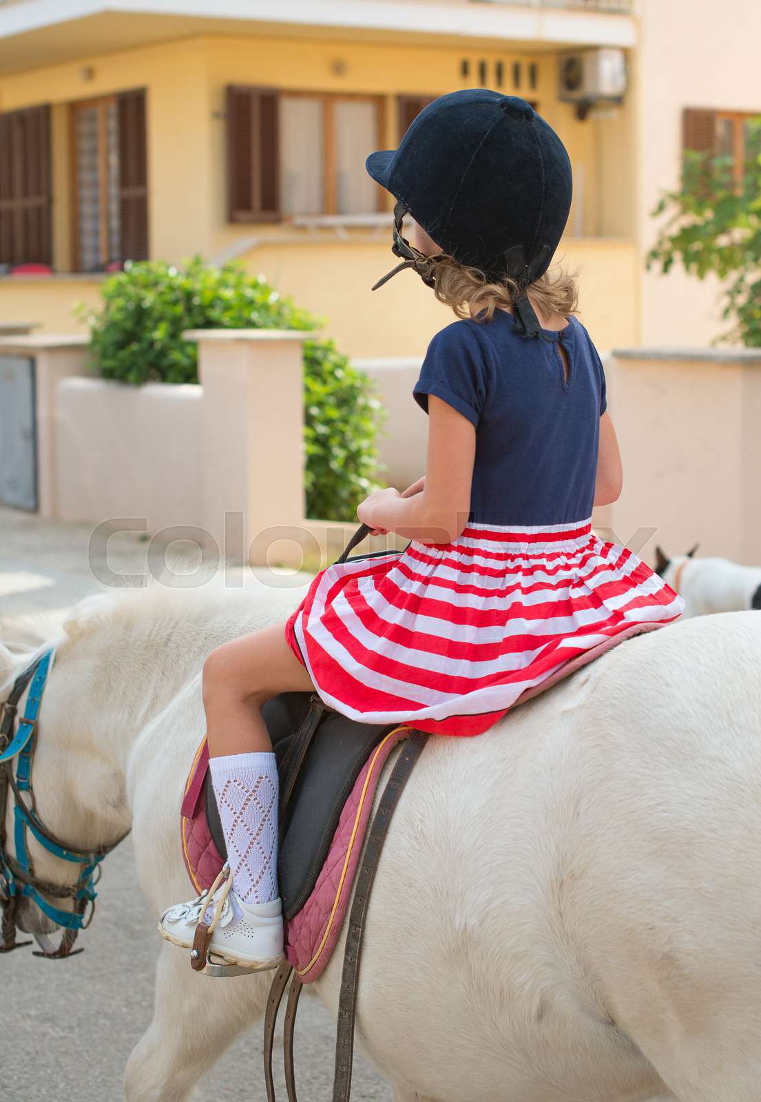 Portrait of little girl riding pony. From the back. | Stock image ...