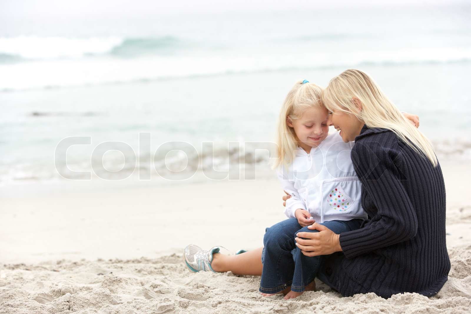 Mutter und Tochter auf Urlaub Sitting On Winter Beach | Stock Bild ...