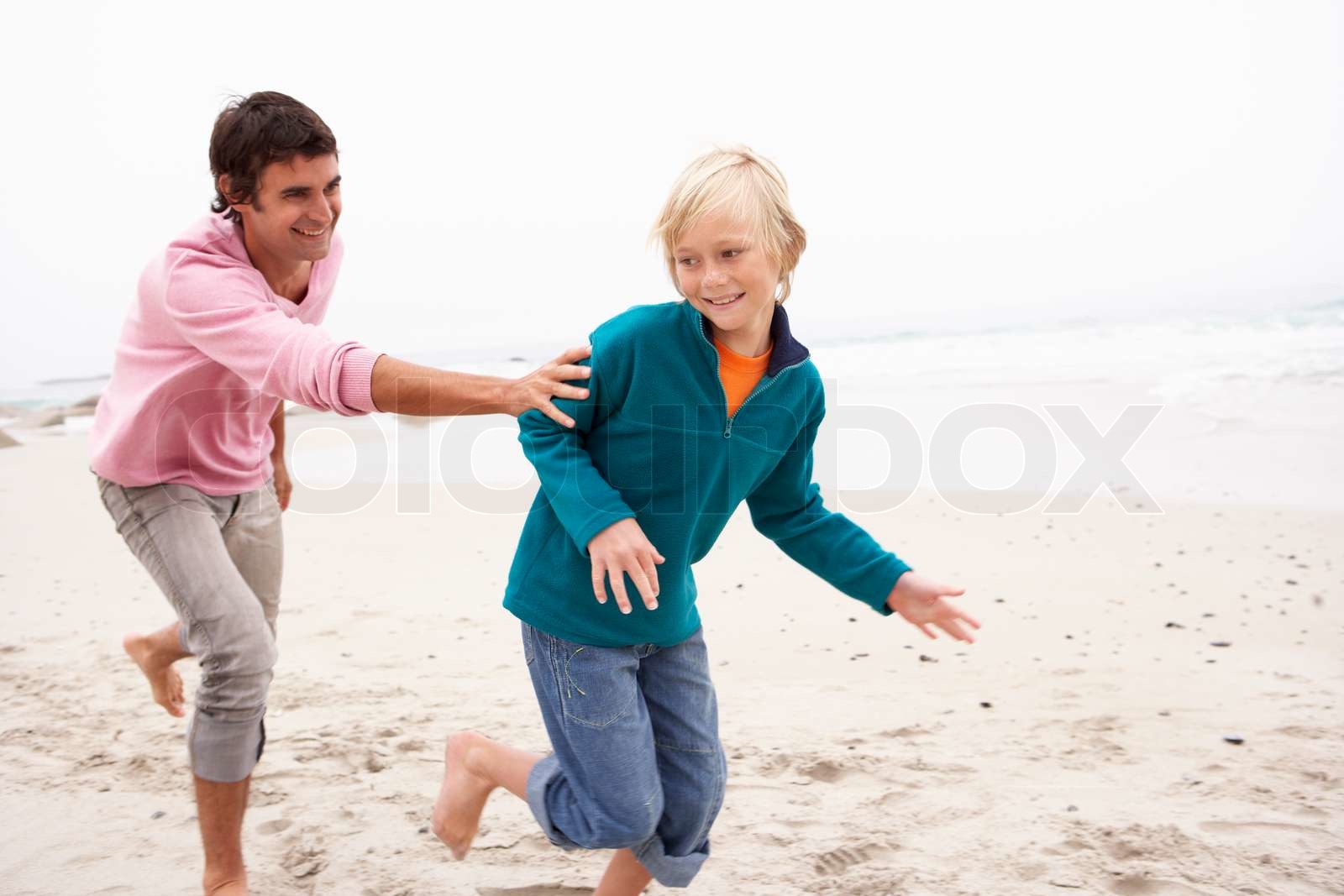 Father Chasing Son Along Winter Beach | Stock image | Colourbox