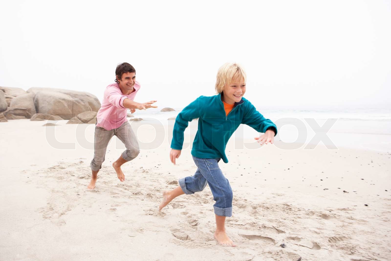 Father Chasing Son Along Winter Beach | Stock image | Colourbox