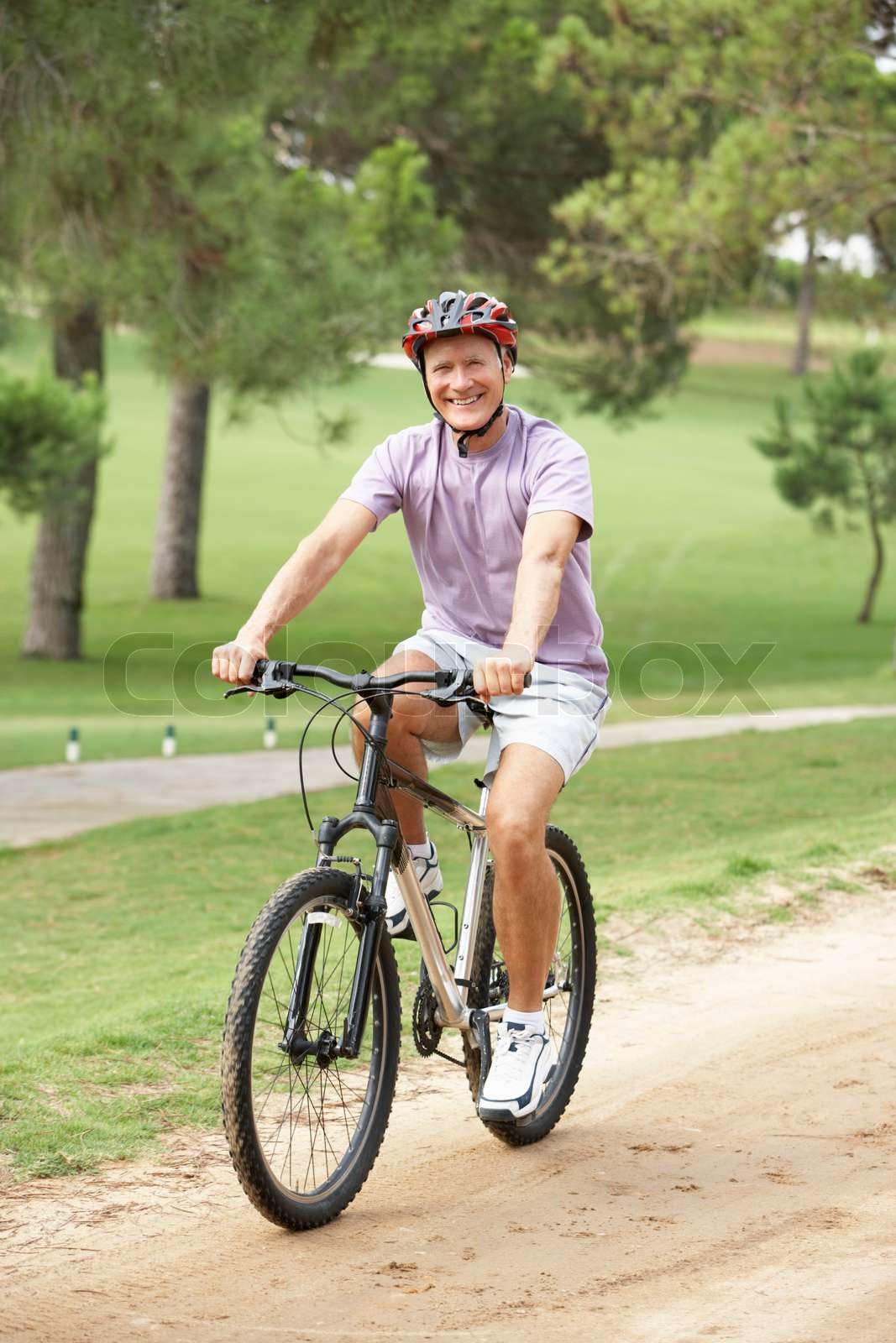 Senior man enjoying bike ride in park | Stock image | Colourbox