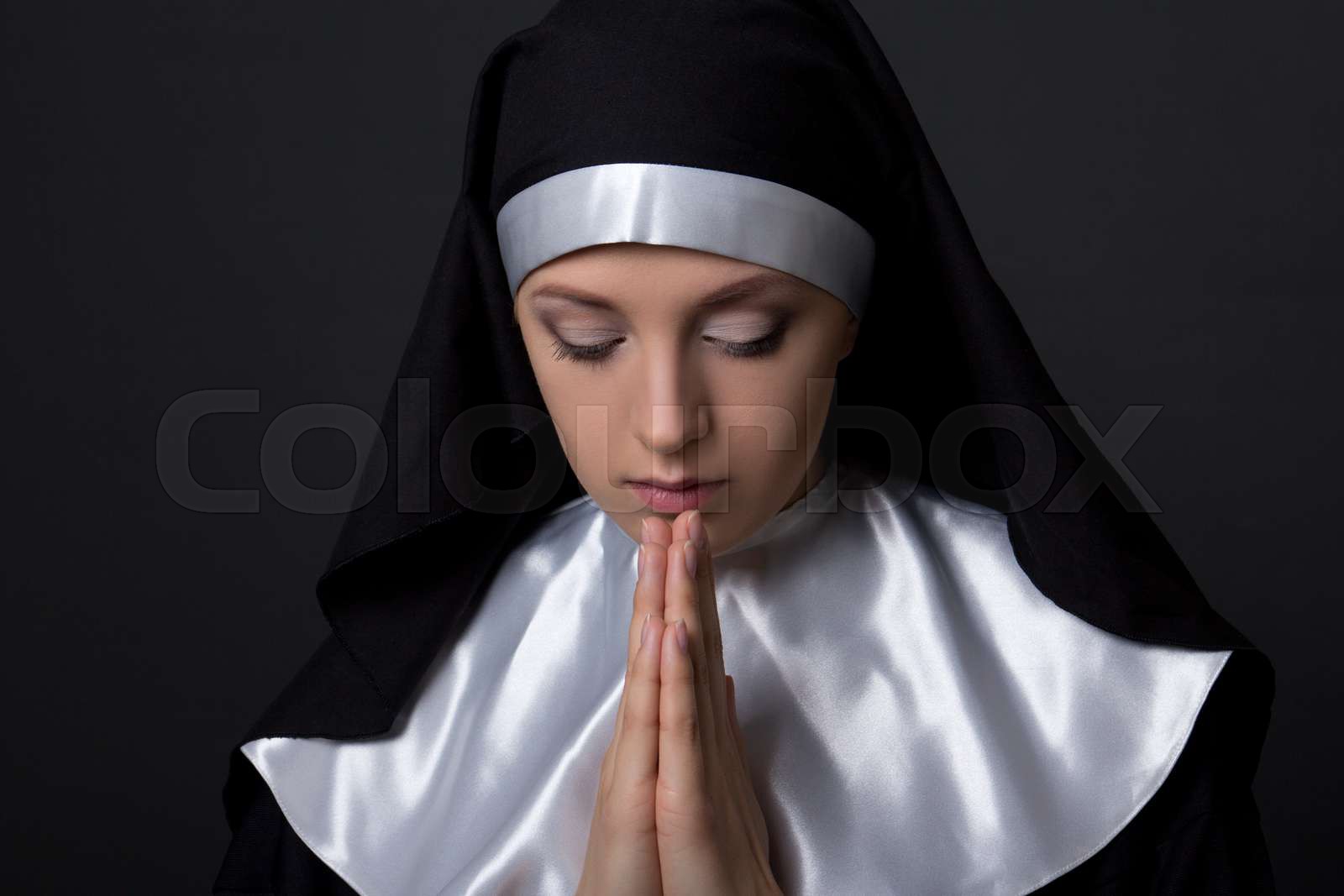 portrait of young beautiful praying nun over grey | Stock image | Colourbox
