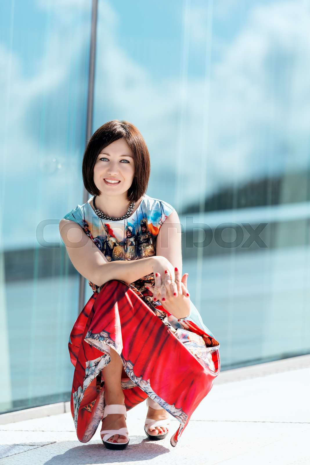 Model in dress posing on exterior set squat | Stock image | Colourbox