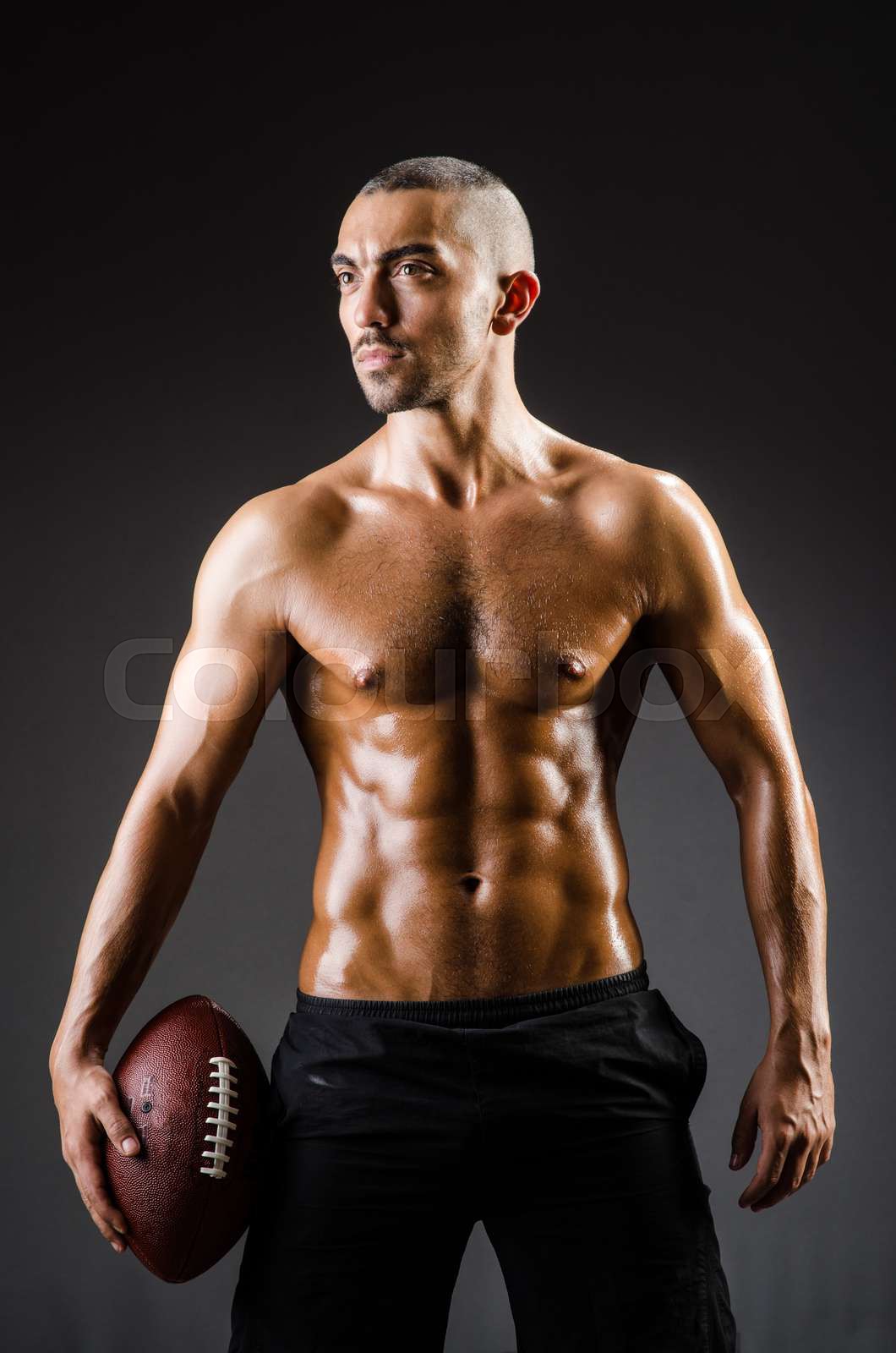 Muscular football player with ball | Stock image | Colourbox