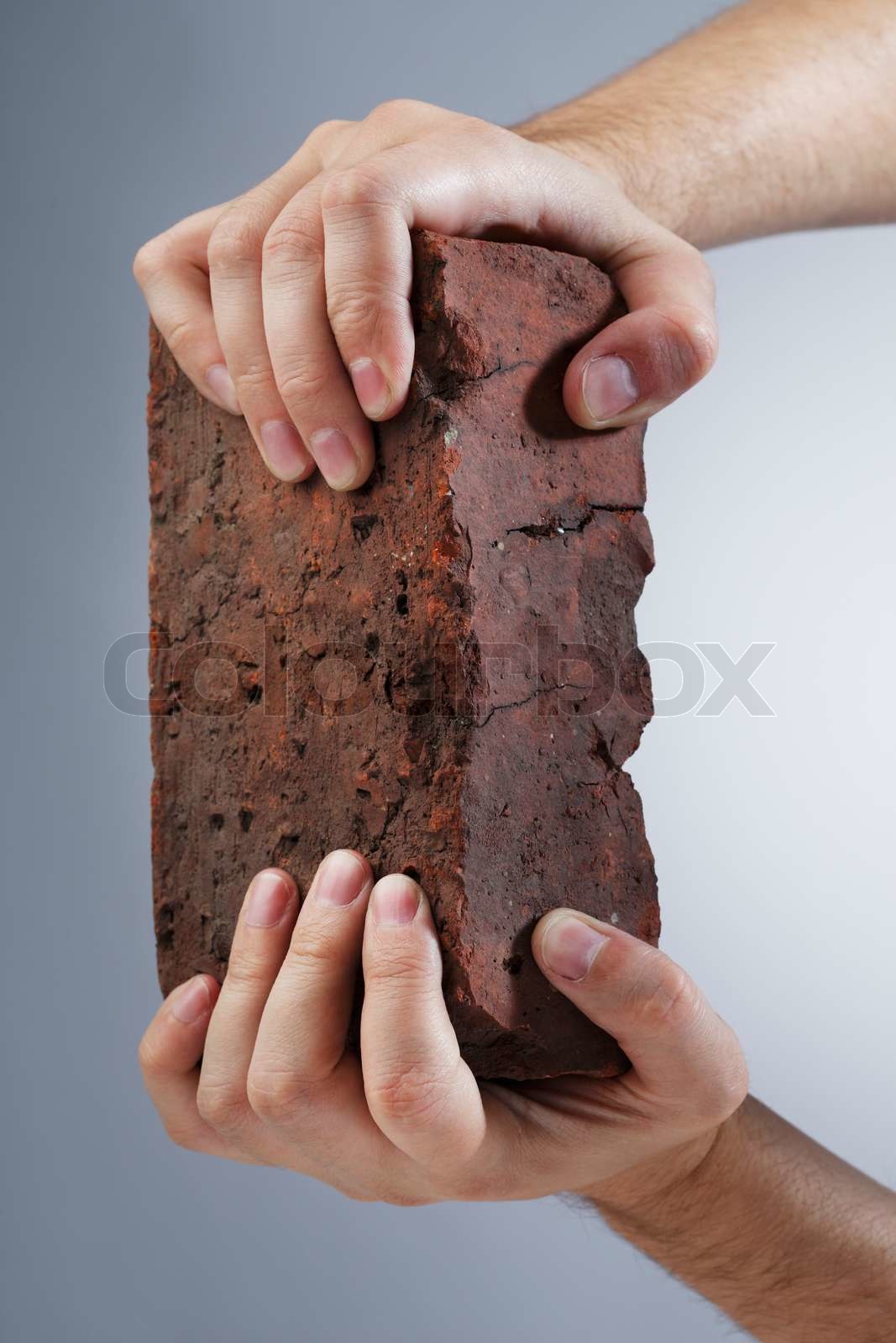 Hands holding an old brick | Stock image | Colourbox