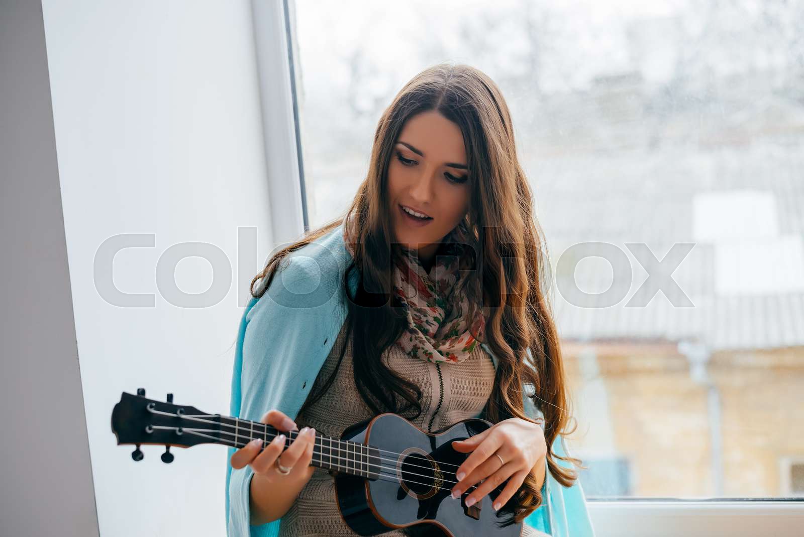 girl sitting on the window. playing guitar | Stock image | Colourbox