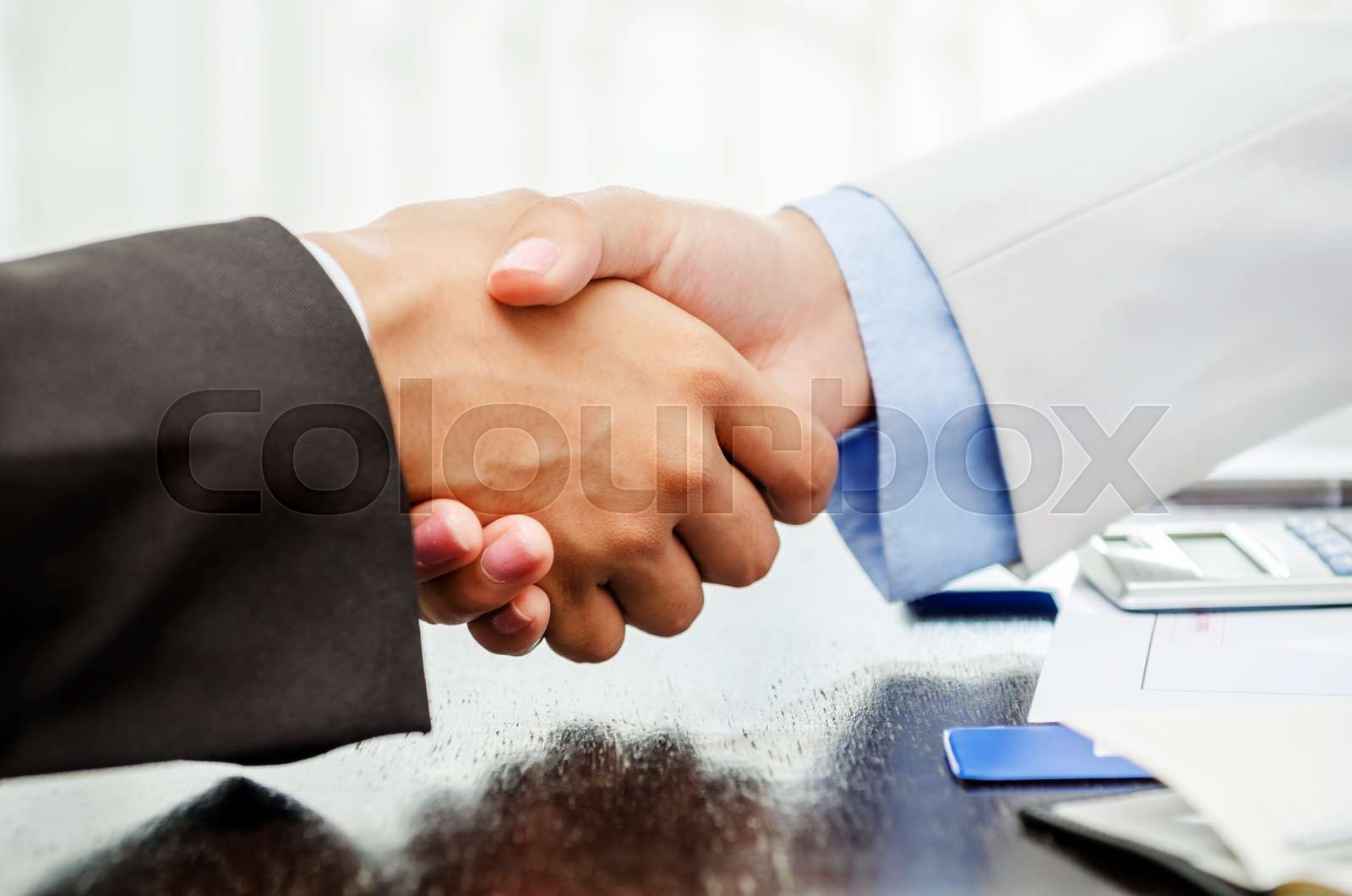 Handshake over document | Stock image | Colourbox