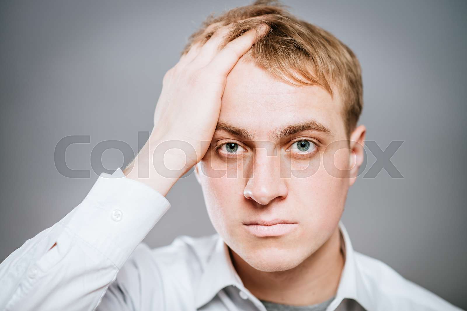 Frustrated man thinking deeply, hand on head. | Stock image | Colourbox