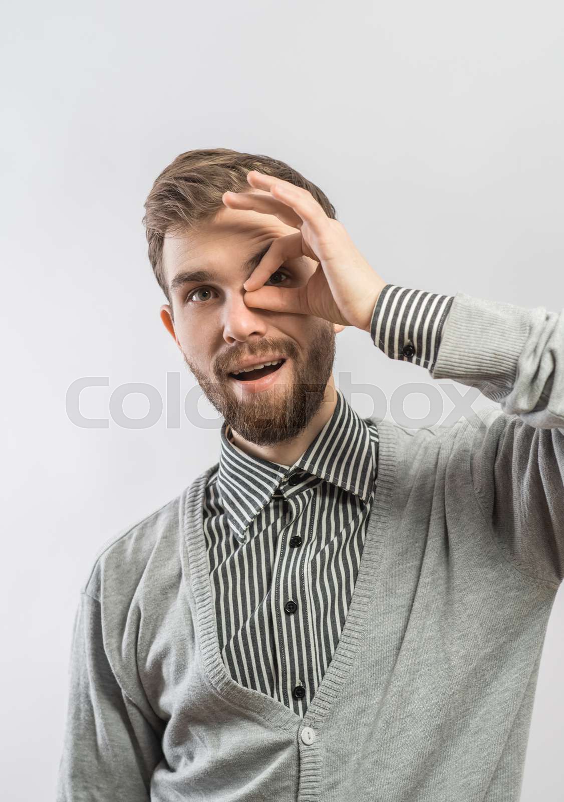 man with hand over eyes, looking through fingers | Stock image | Colourbox