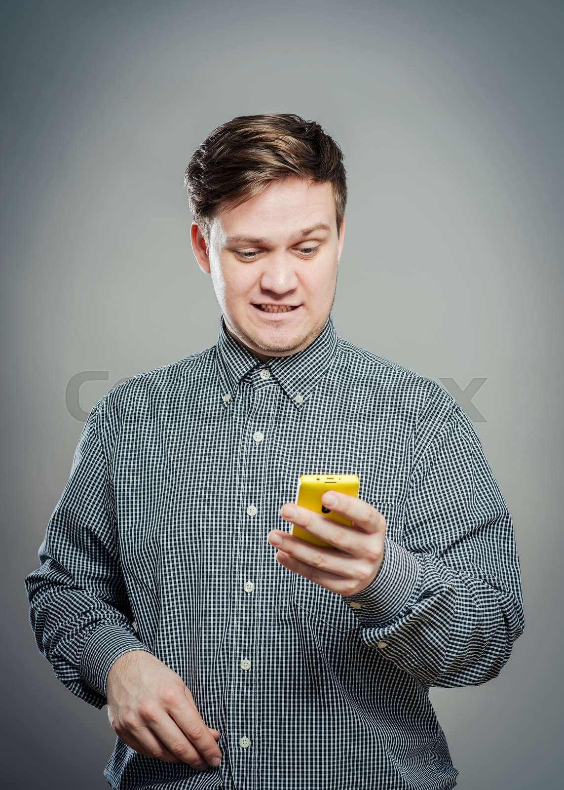 A Confused Young Man Looking At Mobile Phone Stock Image Colourbox