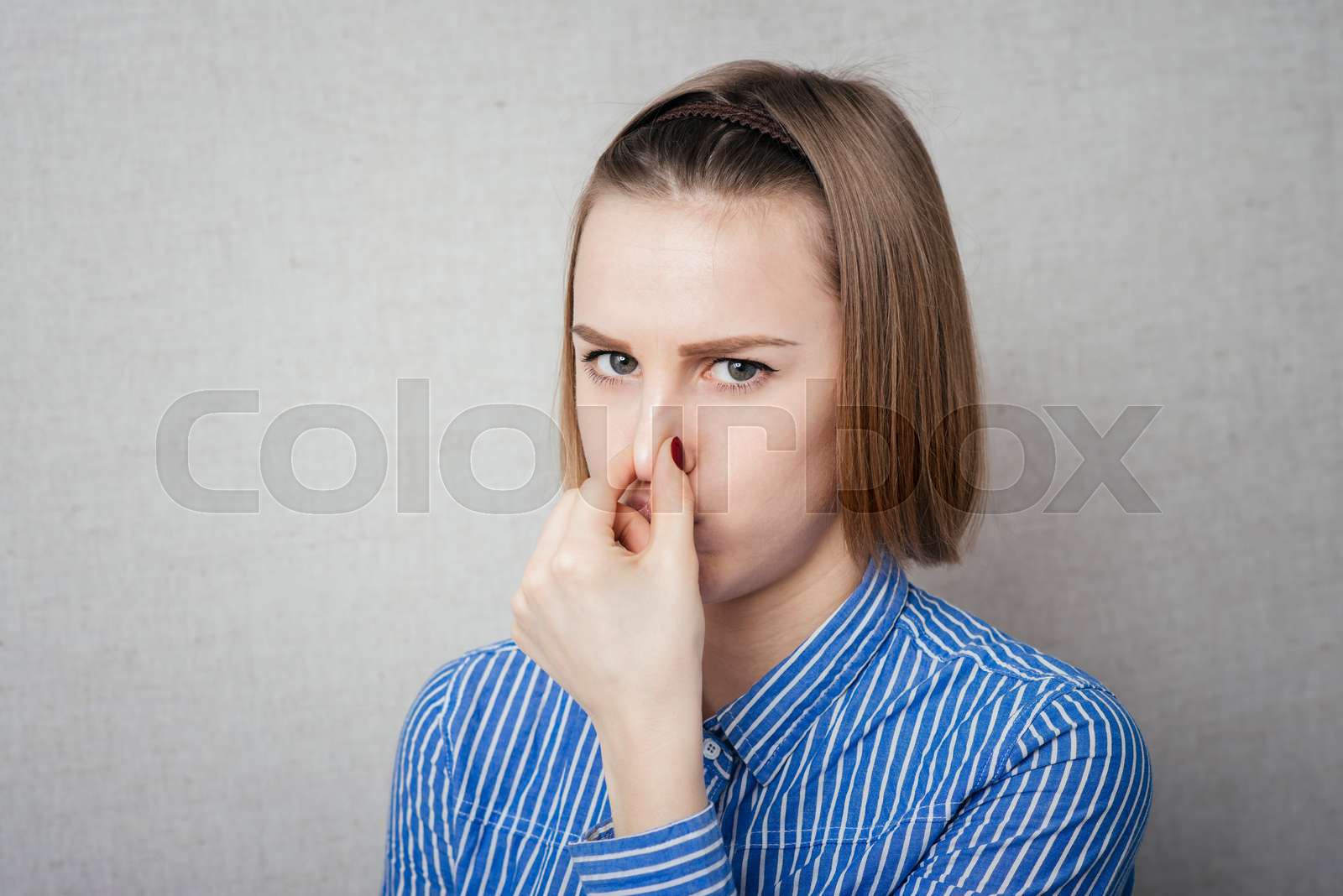Woman disgusted by bad smell holding her nose | Stock image | Colourbox