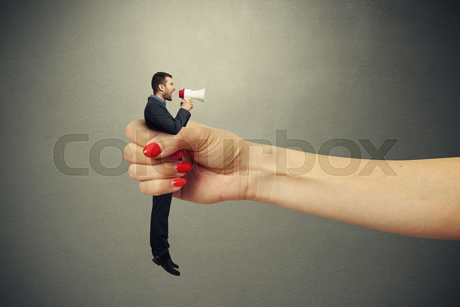 female hand holding in fist small man | Stock image | Colourbox