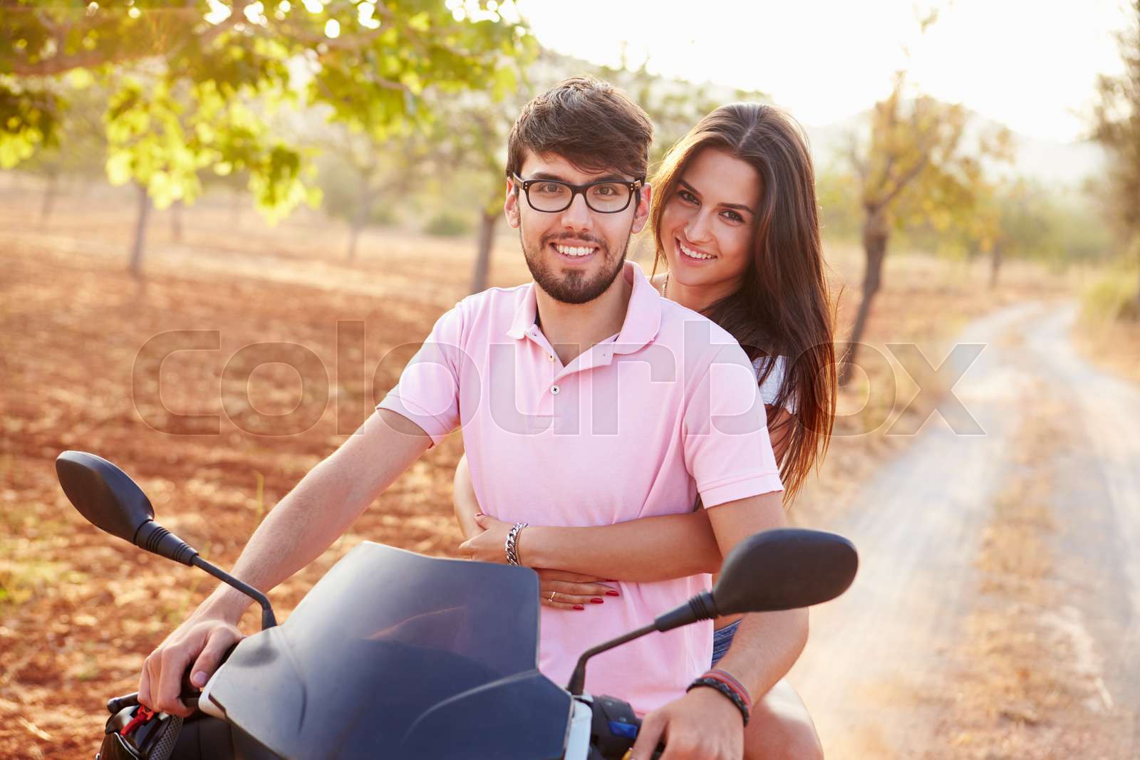 Young Couple Riding Motor Scooter Along Country Road | Stock image ...