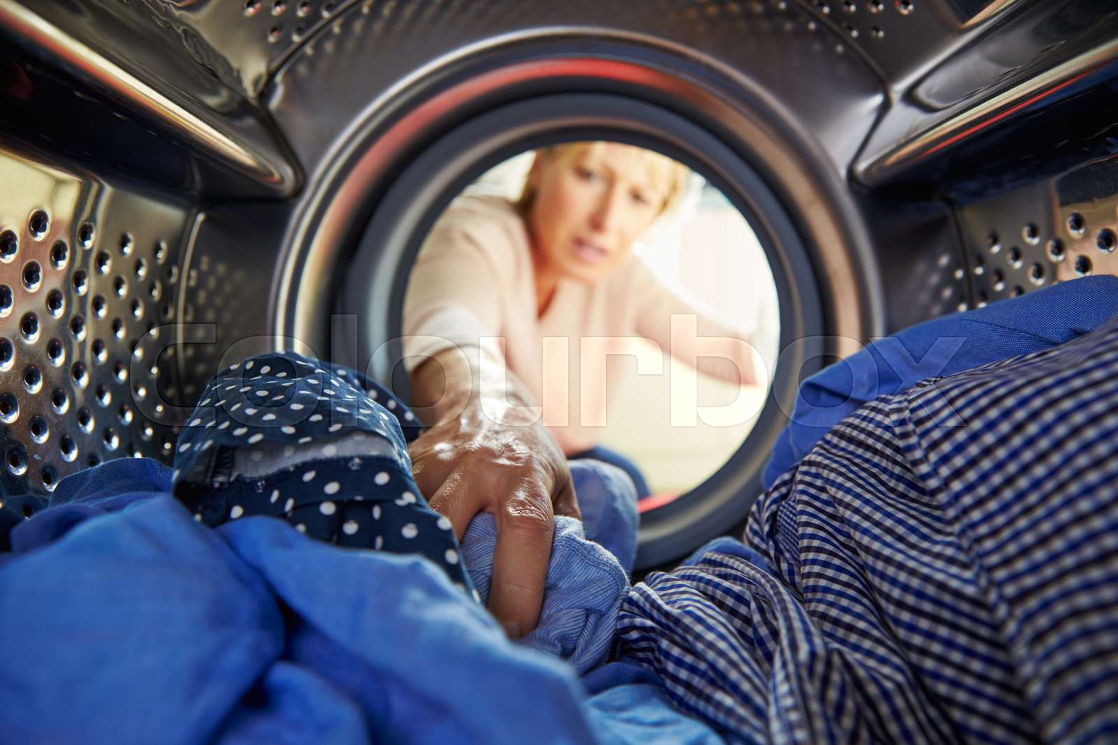 Woman Doing Laundry Reaching Inside Washing Machine | Stock image ...