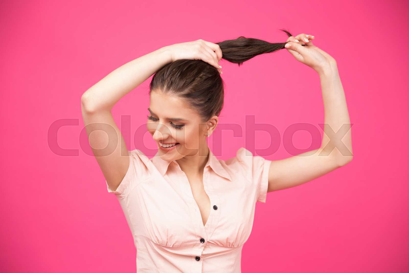 Happy young woman making her hair | Stock image | Colourbox