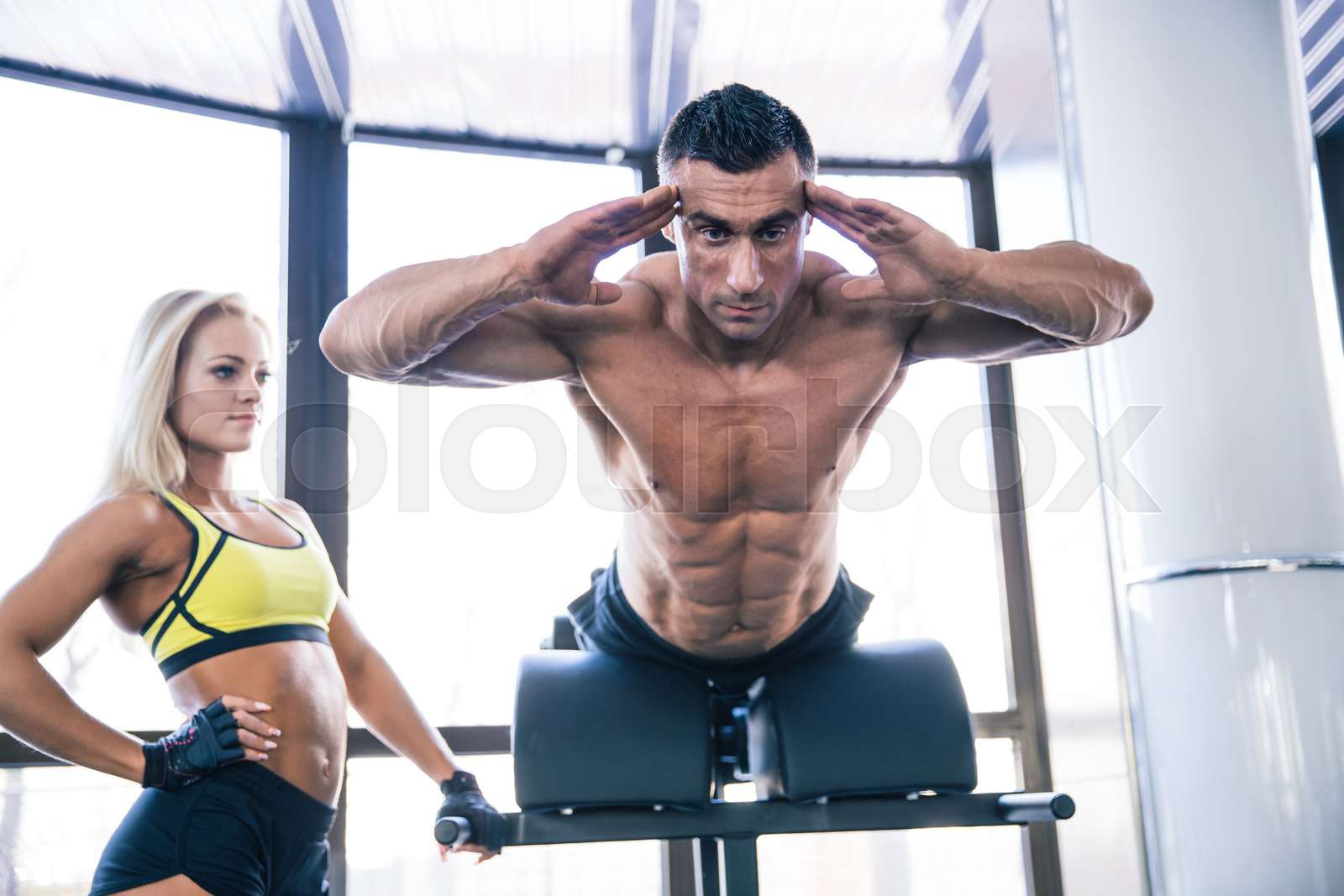 Muscular man flexing back muscles on bench | Stock image | Colourbox