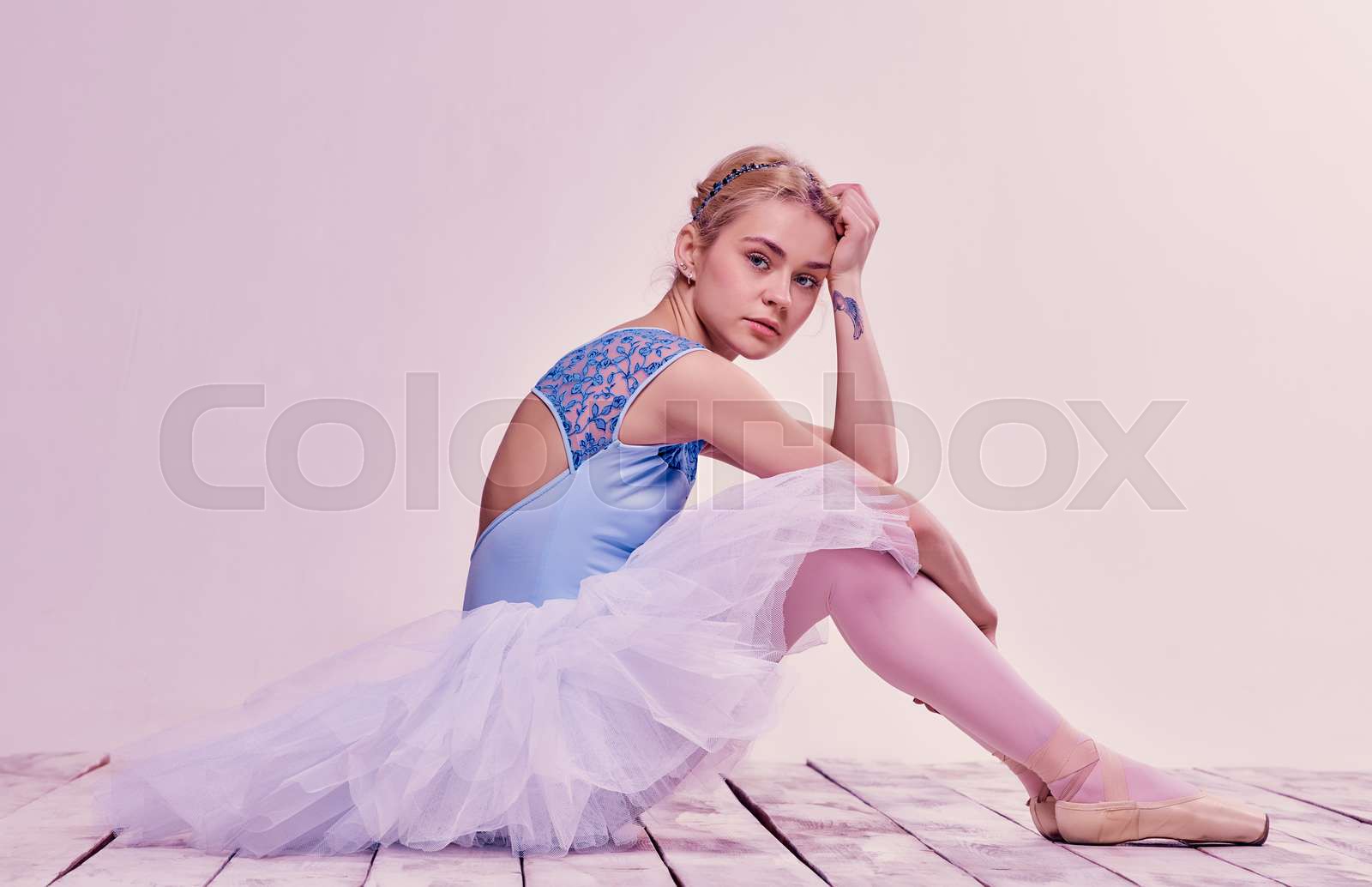 Tired ballet dancer sitting on the wooden floor | Stock image | Colourbox