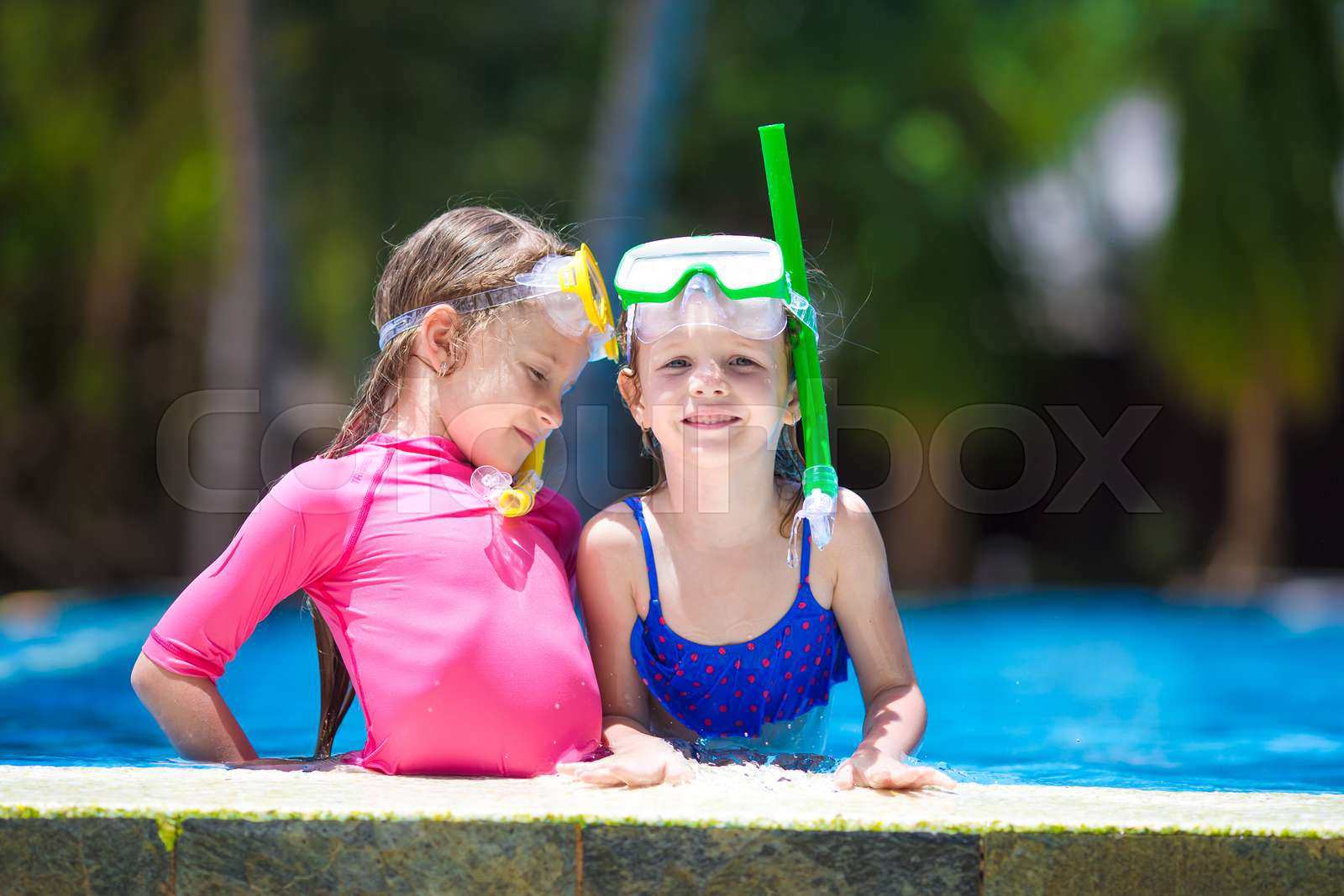 Adorable little girls at mask and goggles in outdoor swimming pool ...