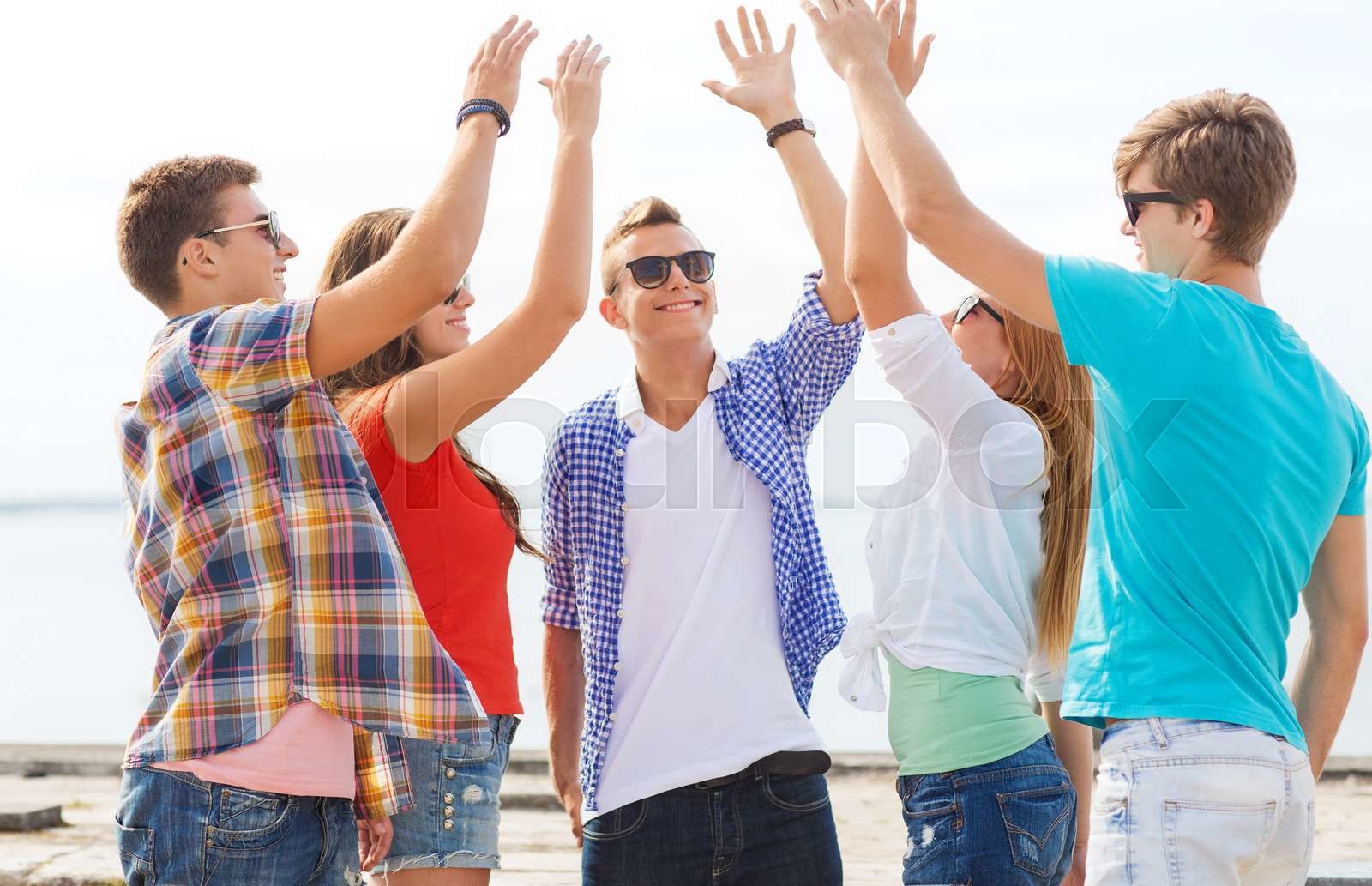 group of smiling friends making high five outdoors | Stock image ...