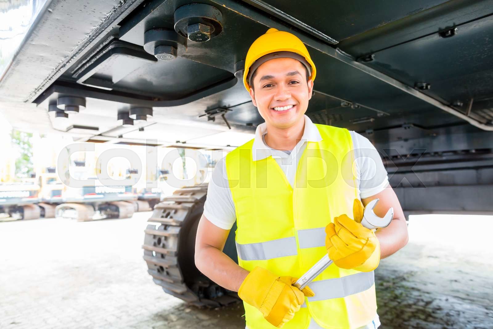 Asian mechanic repairing construction vehicle | Stock image | Colourbox