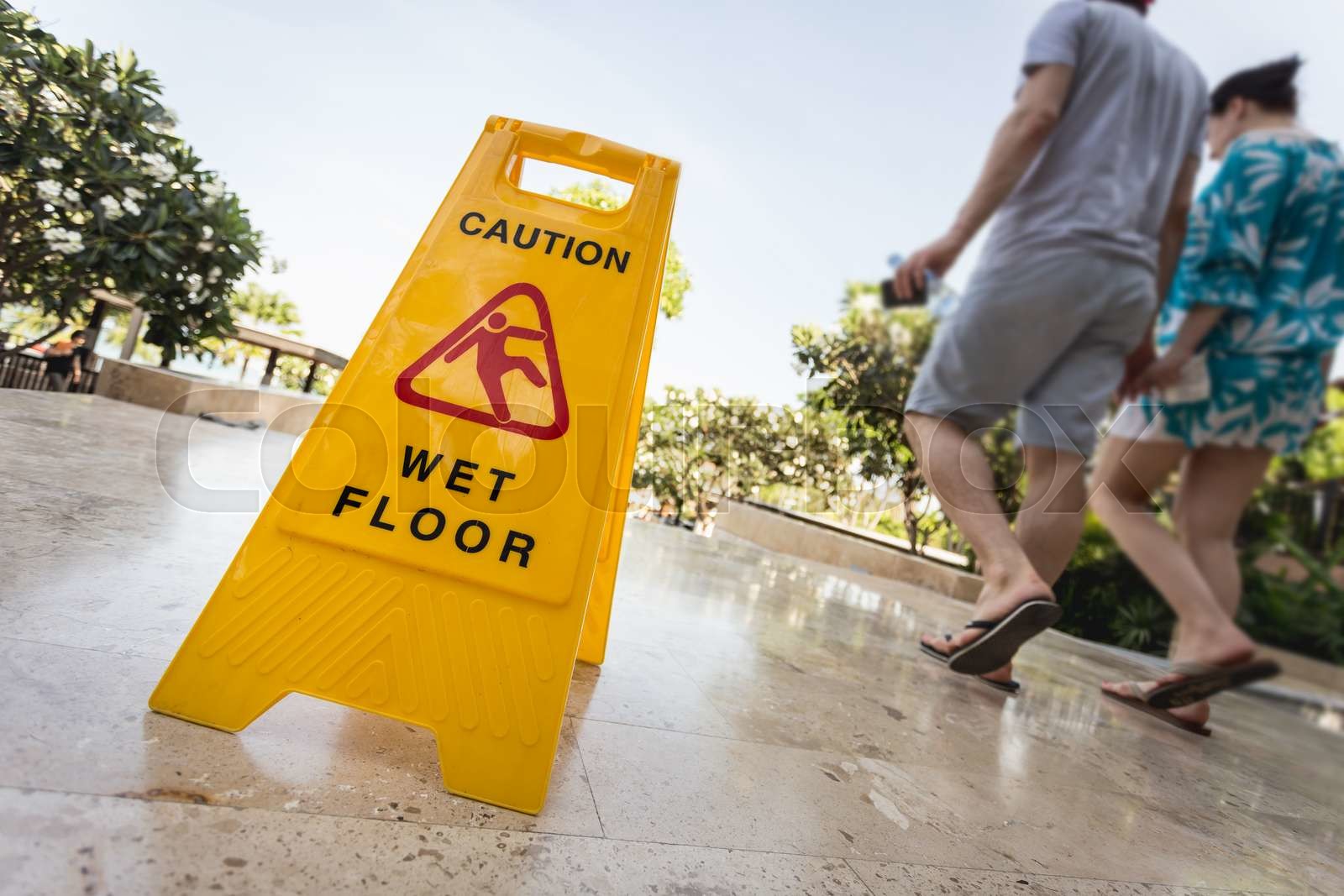 Yellow caution sign and blur of paeple walking on the walkway | Stock ...