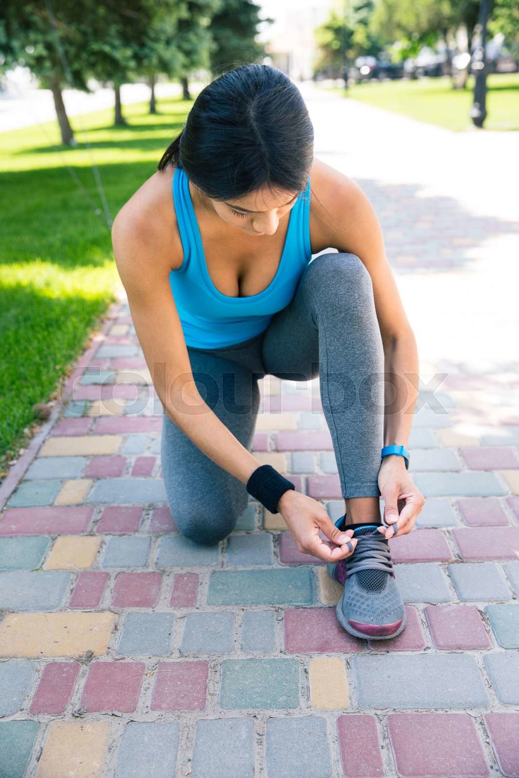 Woman tying her shoelace outdoors | Stock image | Colourbox