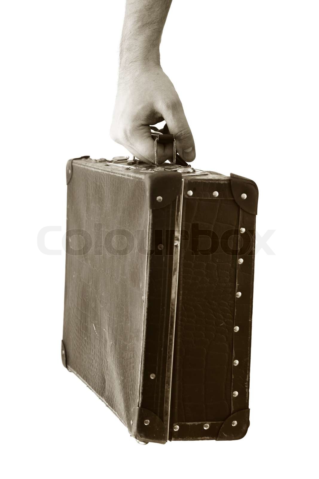 Sepia toned photograph of a hand holding an old suitcase. Short depth ...