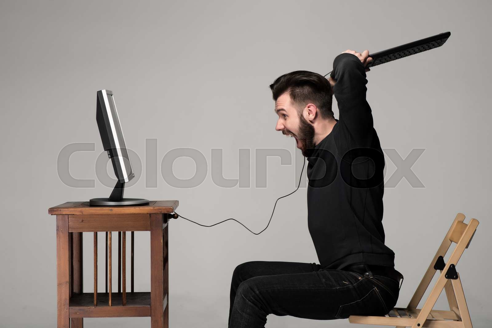 Angry man is destroying a keyboard | Stock image | Colourbox