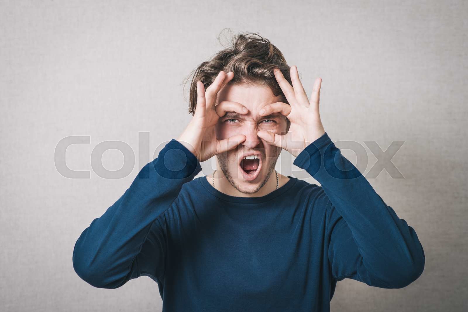 young man with hand over eyes, looking through fingers | Stock image ...