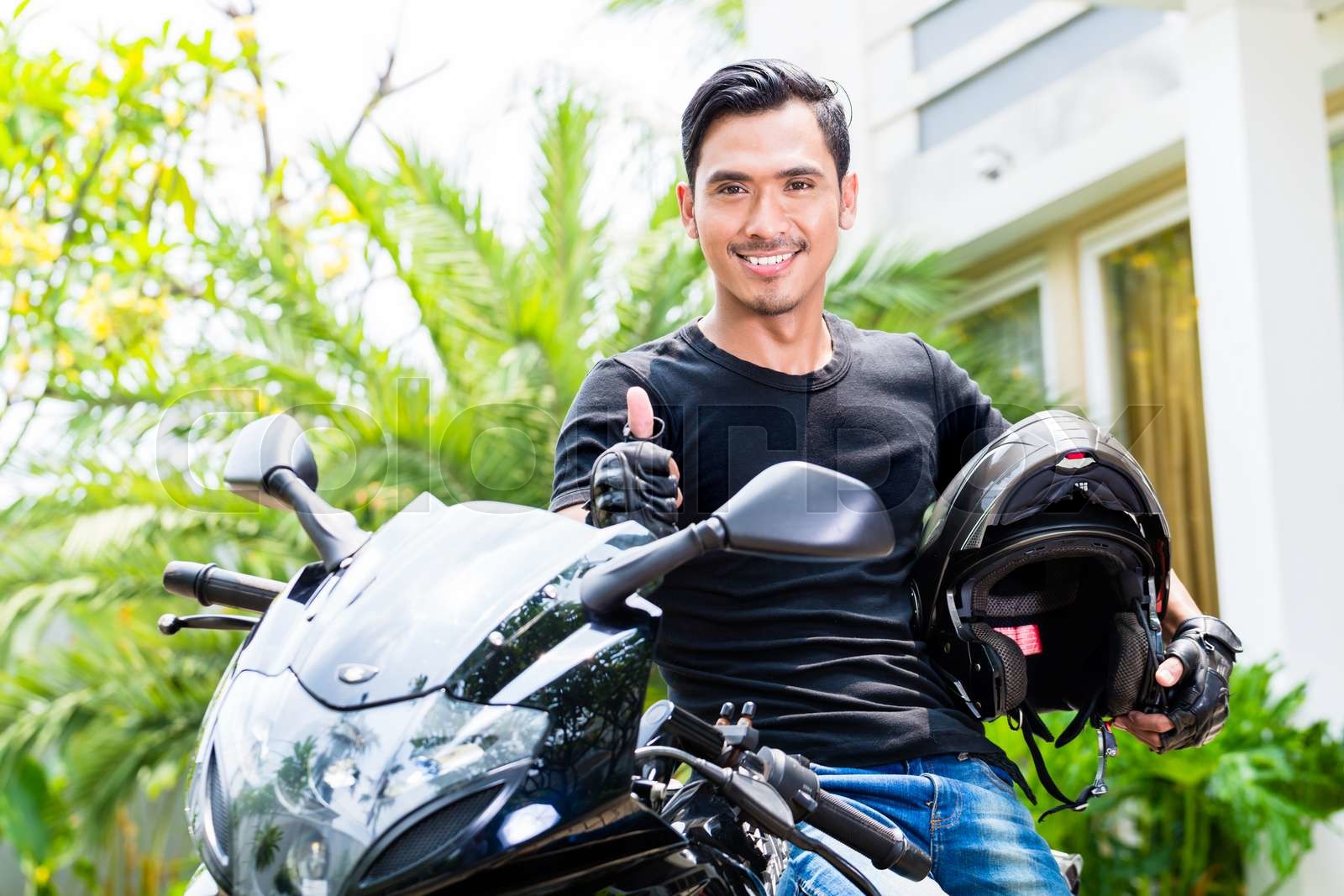 Asian young man and his motorcycle or scooter | Stock image | Colourbox