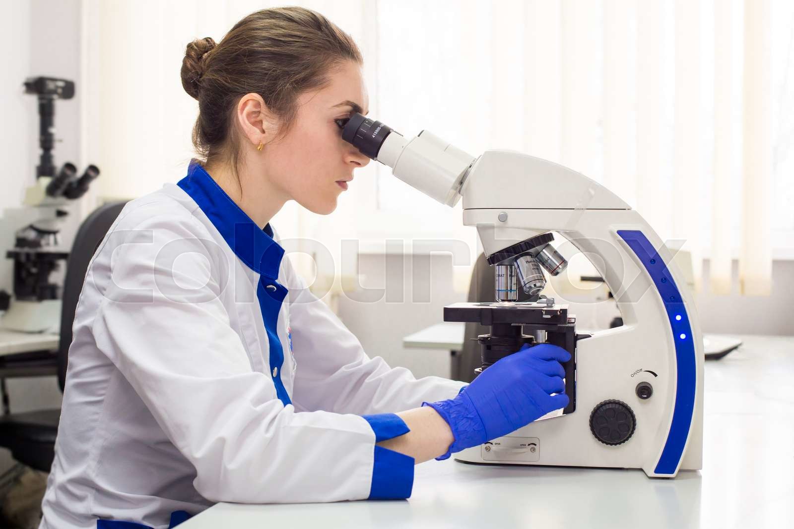 Medical worker looking into a microscope | Stock image | Colourbox
