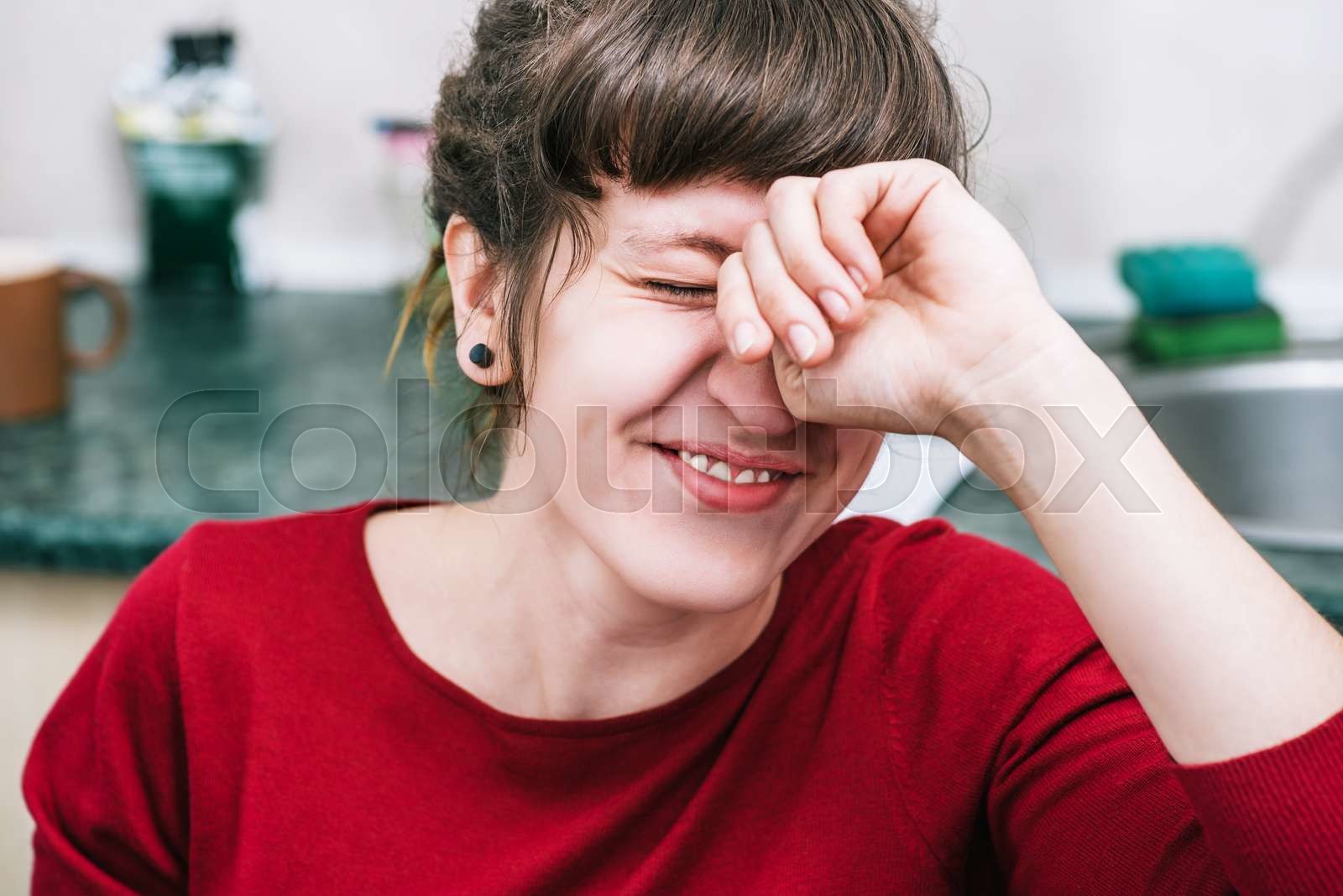 Woman covering her face laughing. In the house. | Stock image | Colourbox