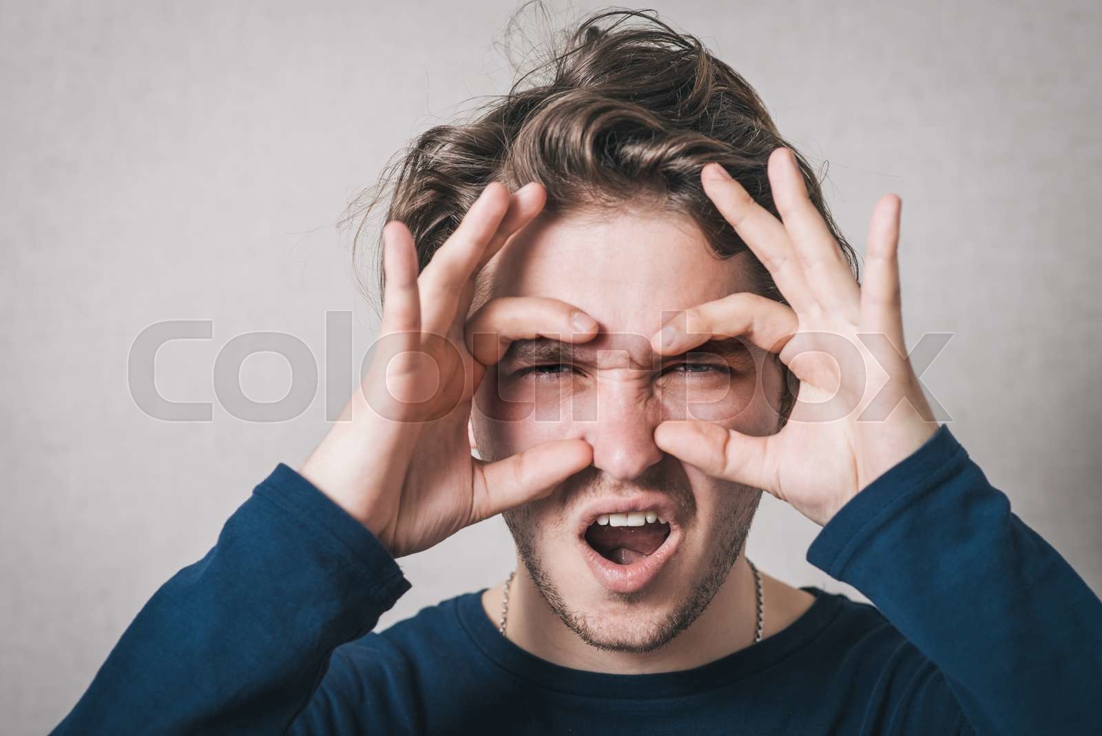 young man with hand over eyes, looking through fingers | Stock image ...