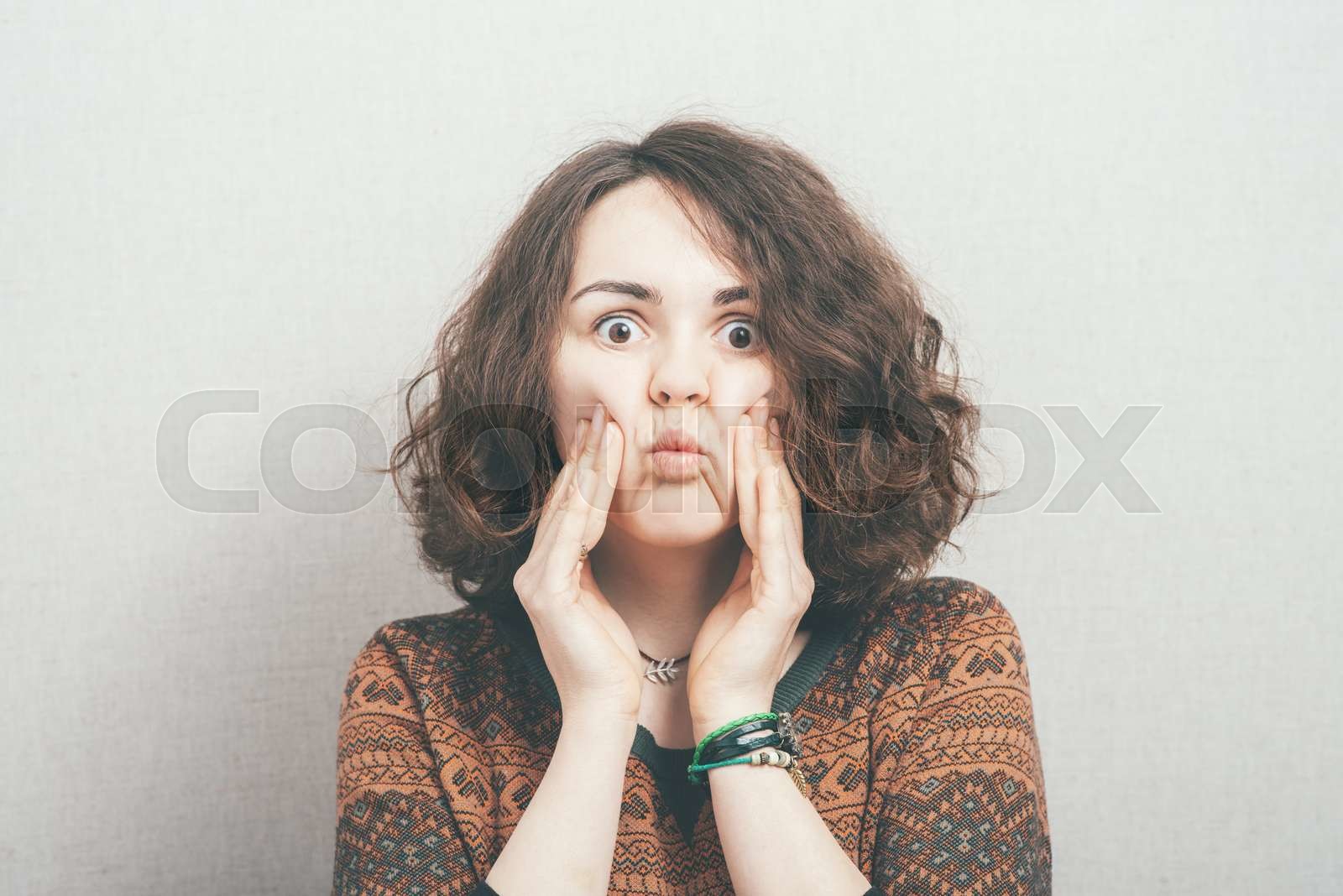 Young woman squeezing her cheeks with her hands | Stock image | Colourbox